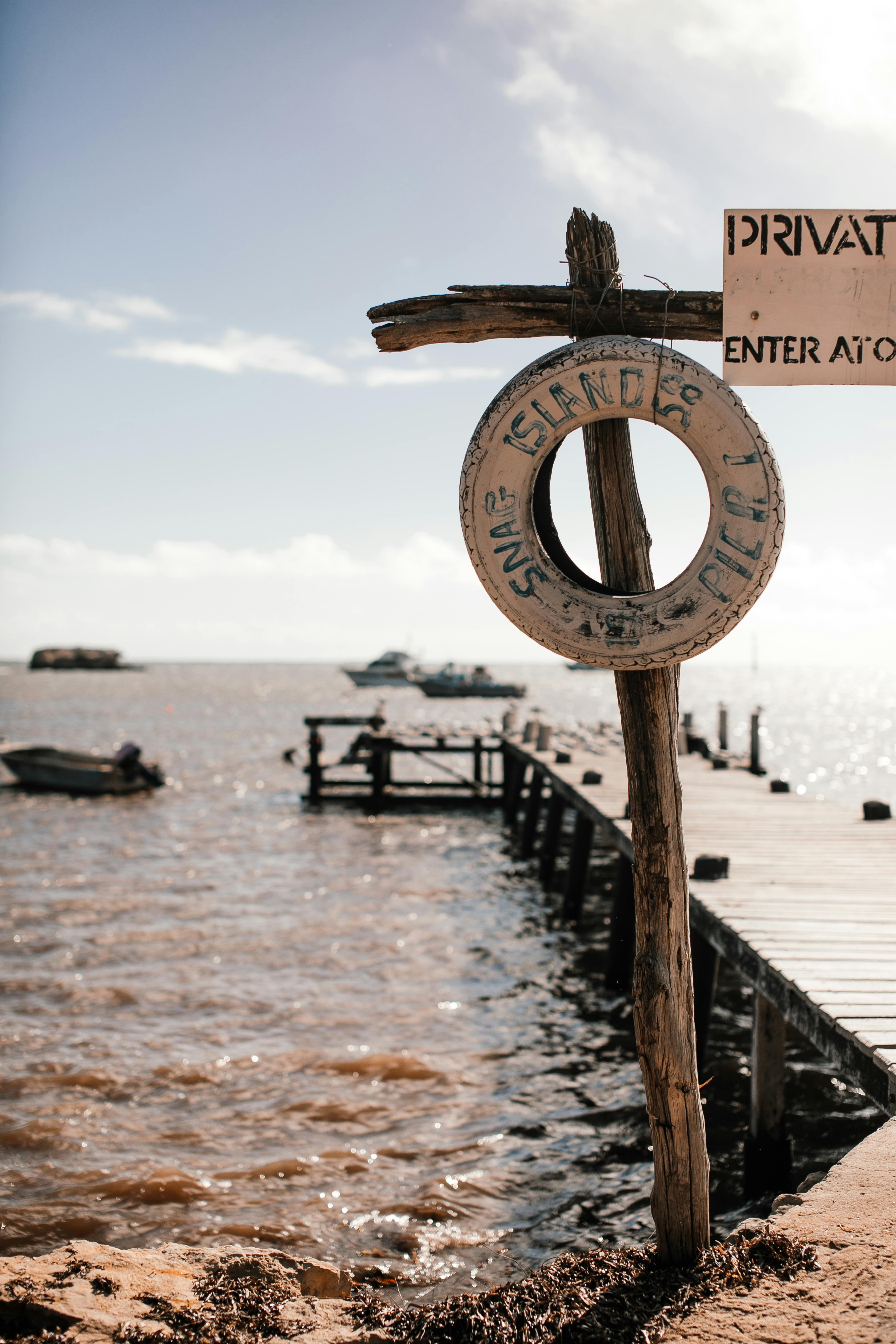 Sign at Pier near Splashing Sea · Free Stock Photo