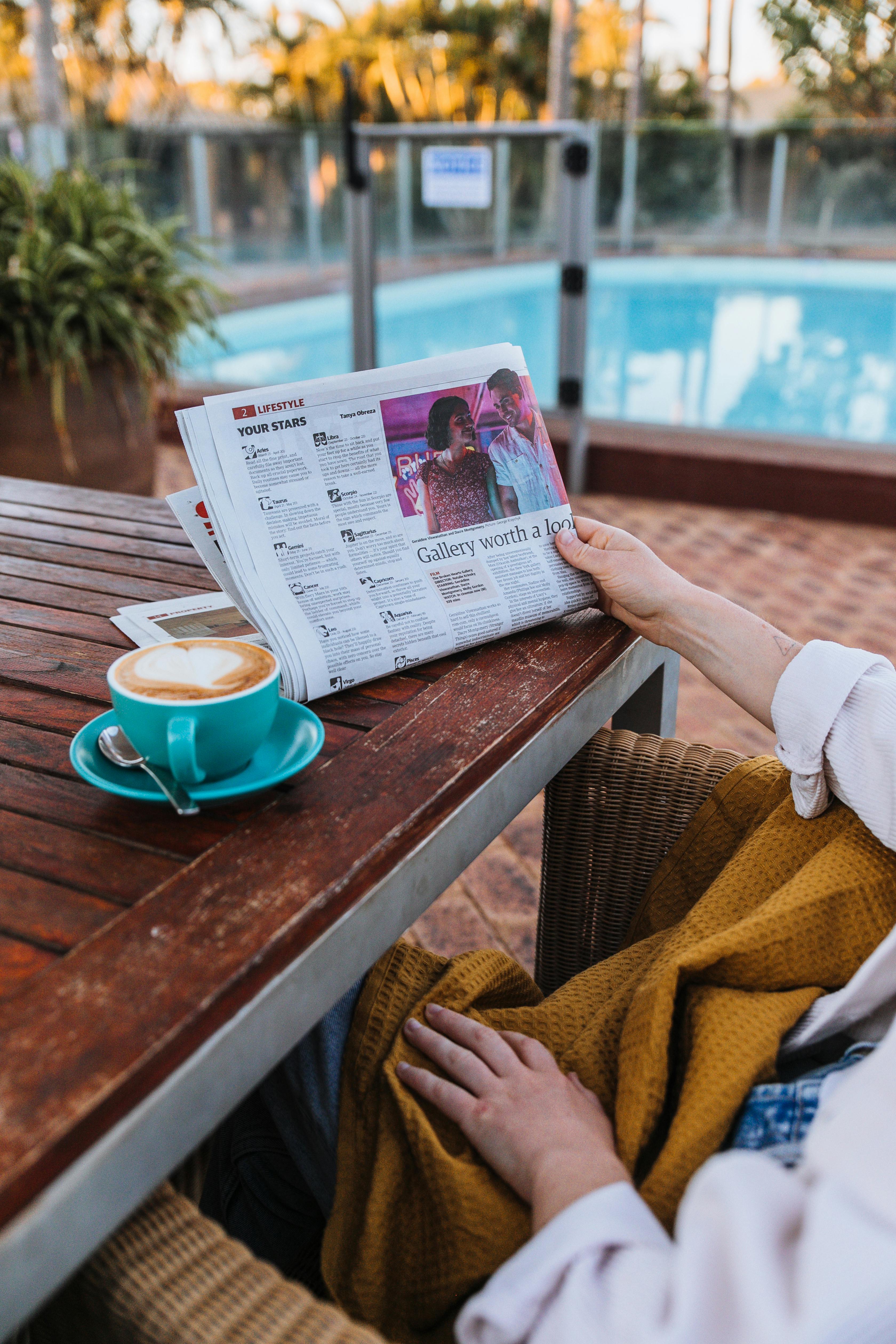 Person Reading Newspaper on Brown Table · Free Stock Photo