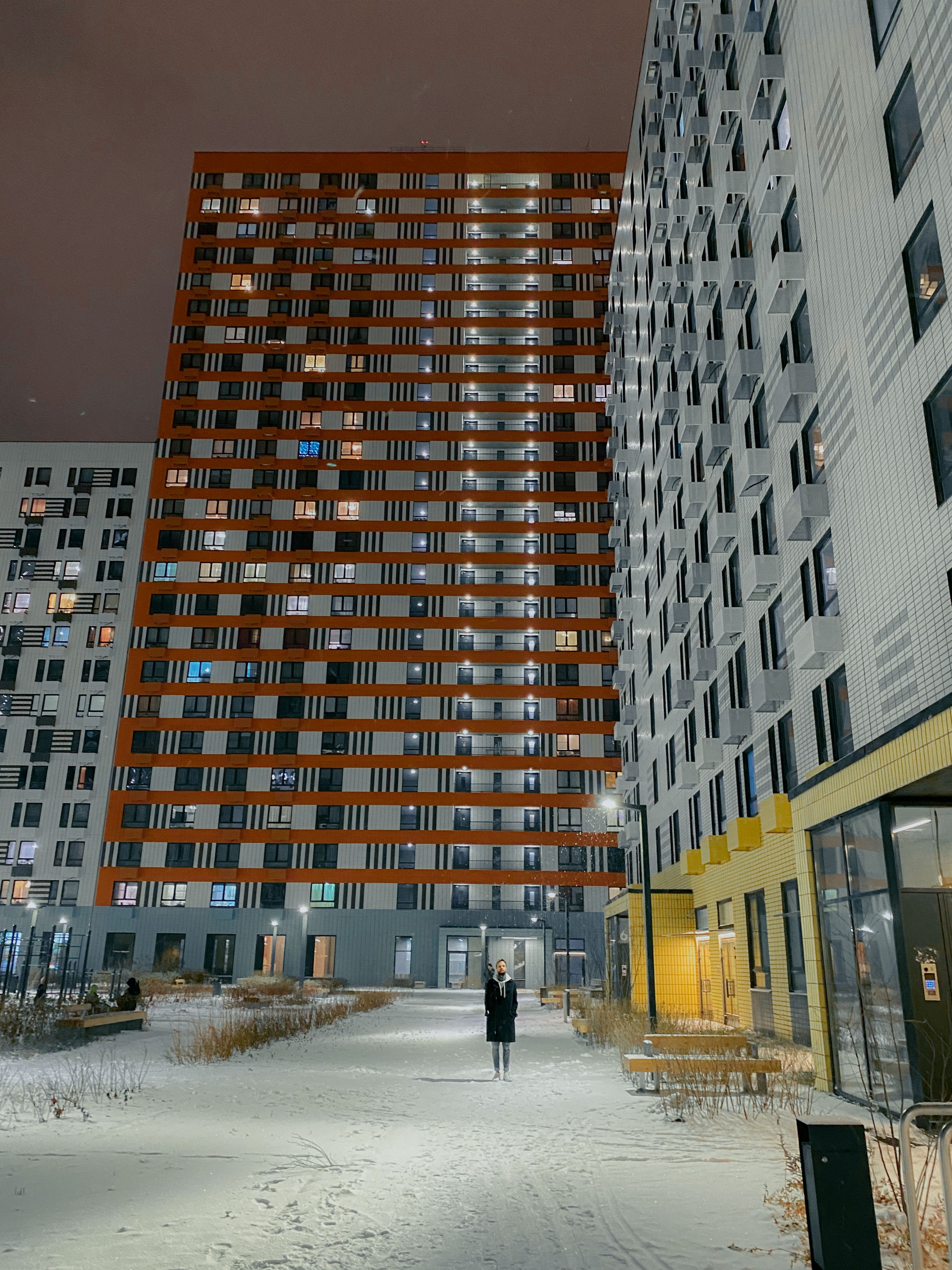Unrecognizable person walking on street towards building entrance ...