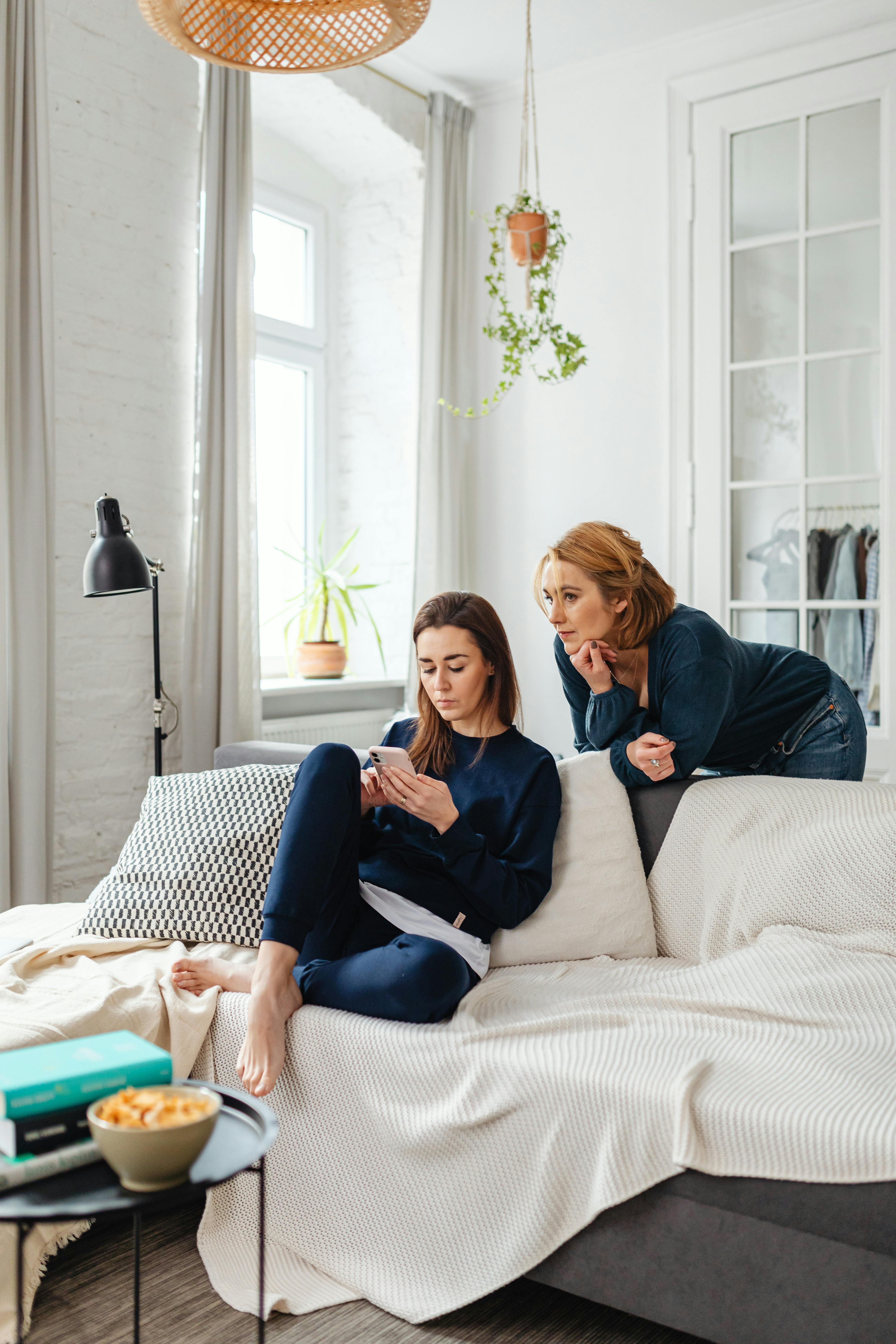 Women in a Living Room, One Using a Smart Phone · Free Stock Photo