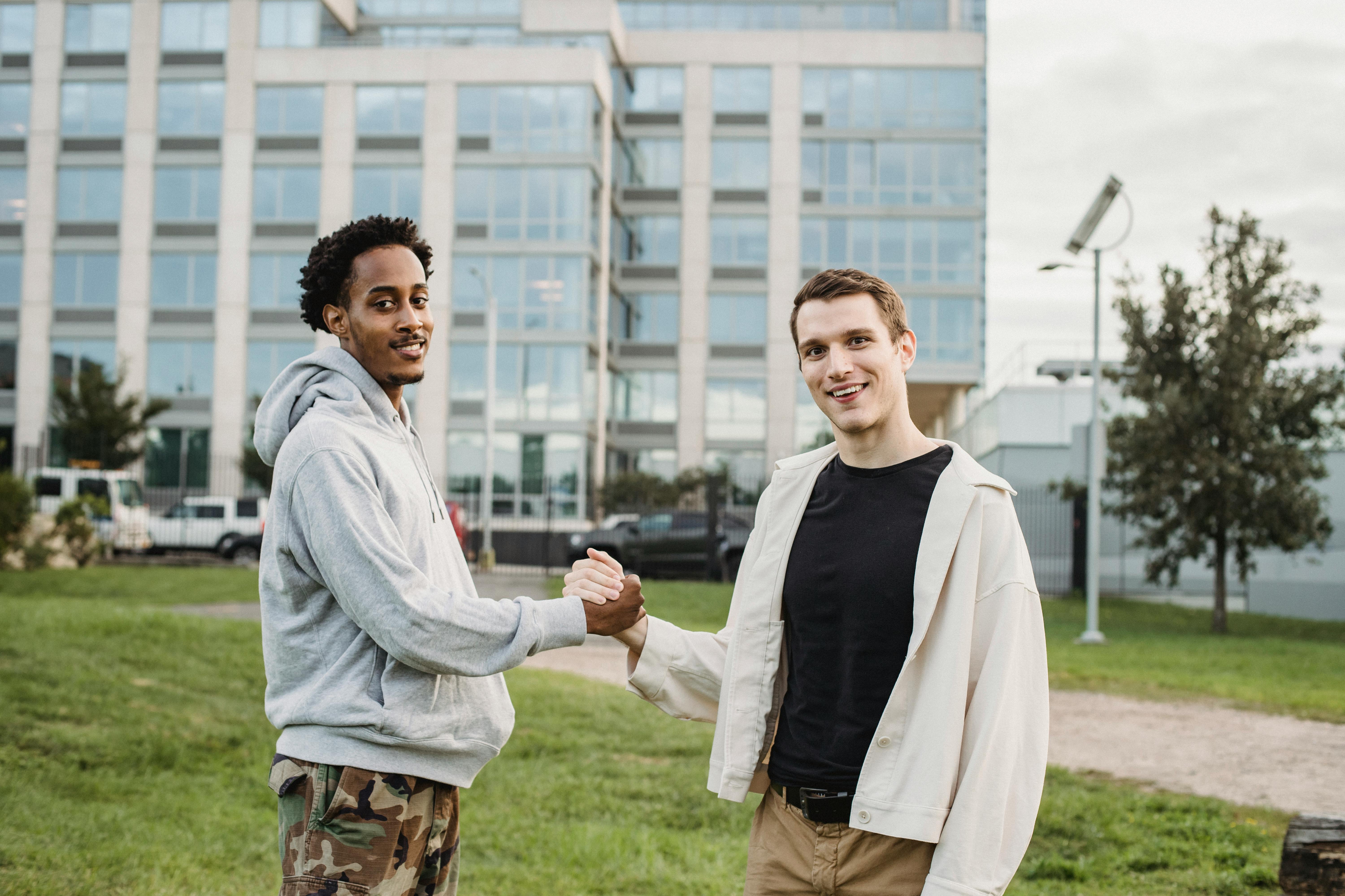 Positive multiethnic friends greeting each other with handshake · Free ...