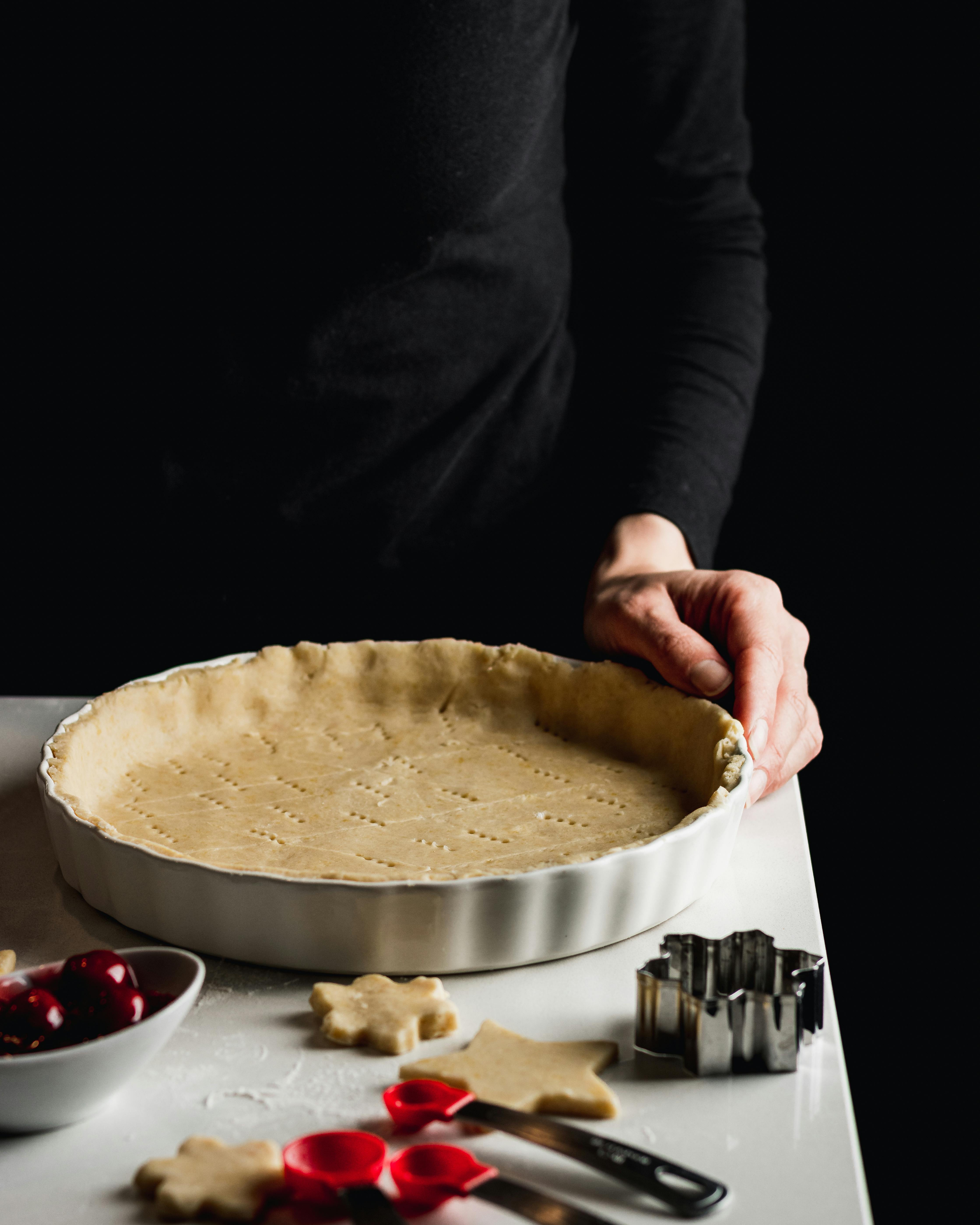Person Holding Pie on White Table · Free Stock Photo