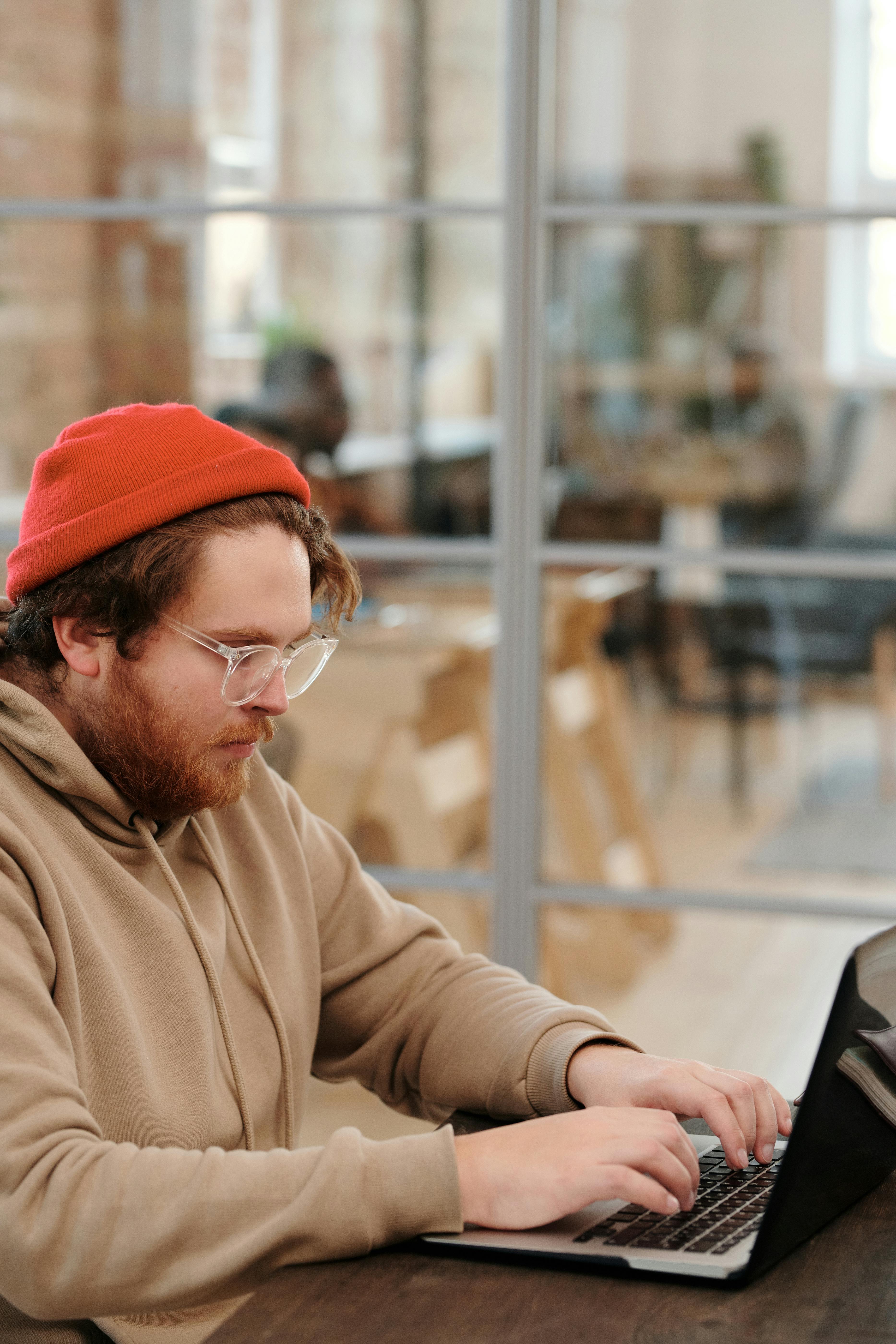 Man in Brown Hoodie Using a Laptop · Free Stock Photo