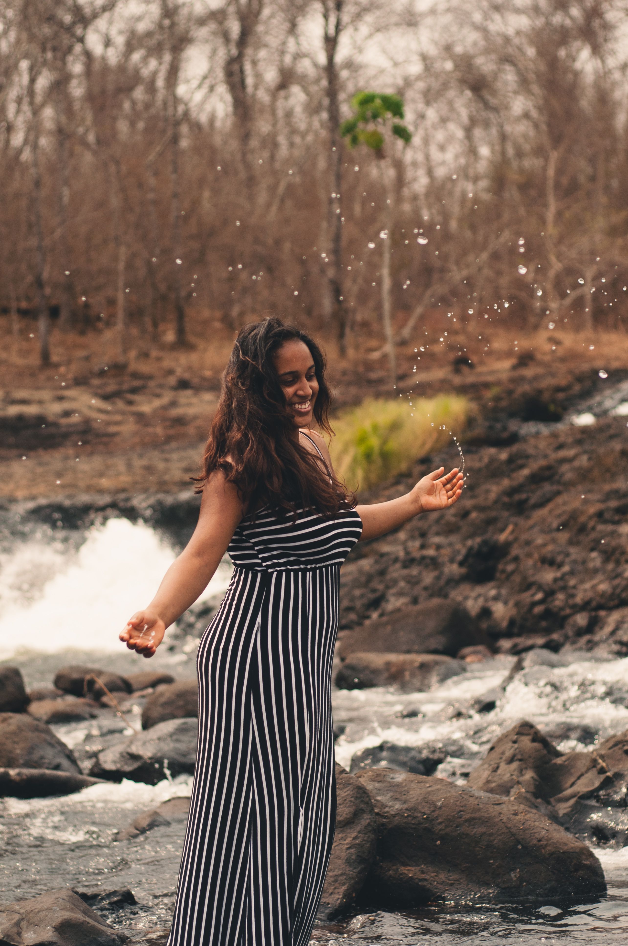 Cheerful ethnic woman splashing water of creek · Free Stock Photo