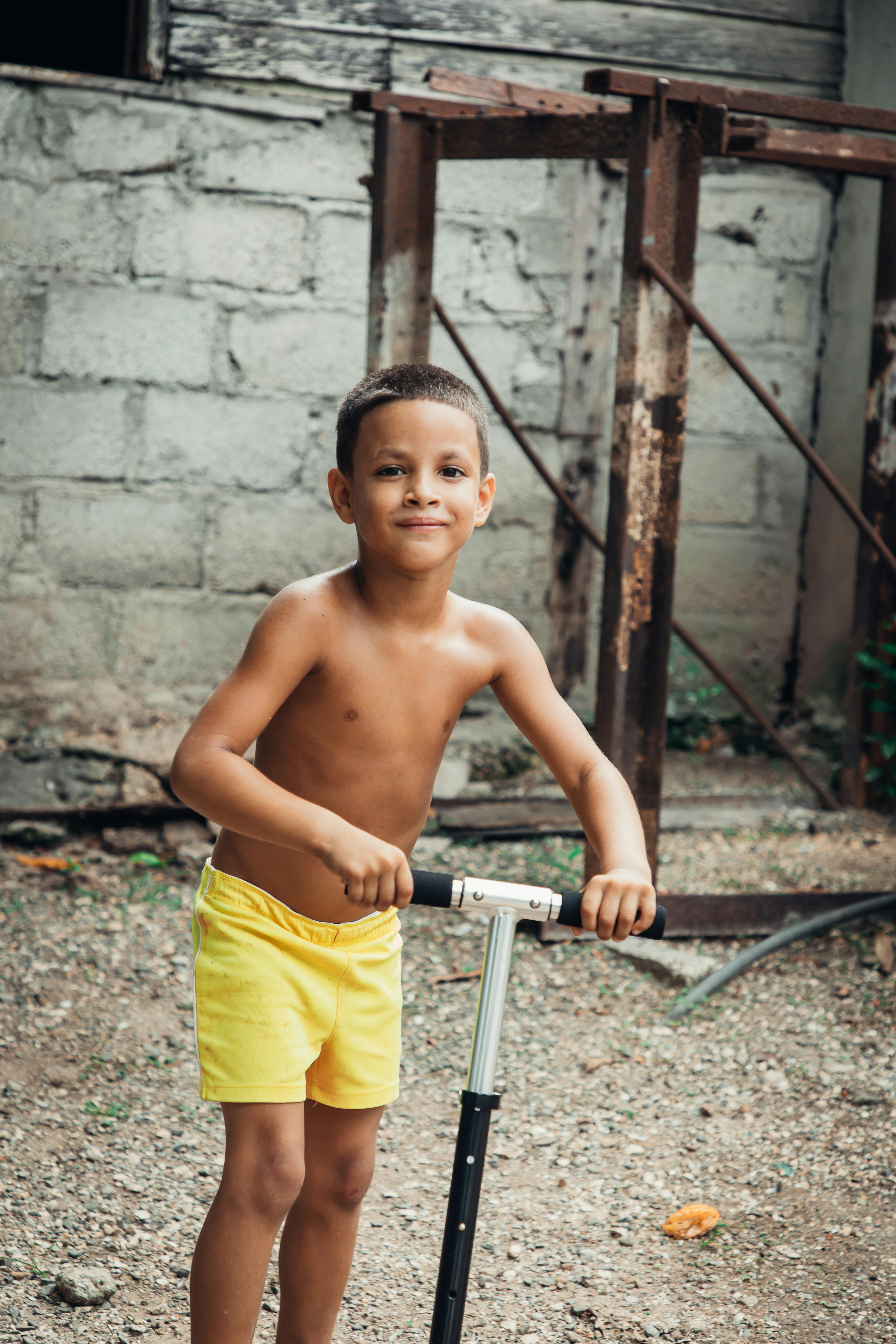 A Shirtless Boy Wearing Jeans and Slippers · Free Stock Photo