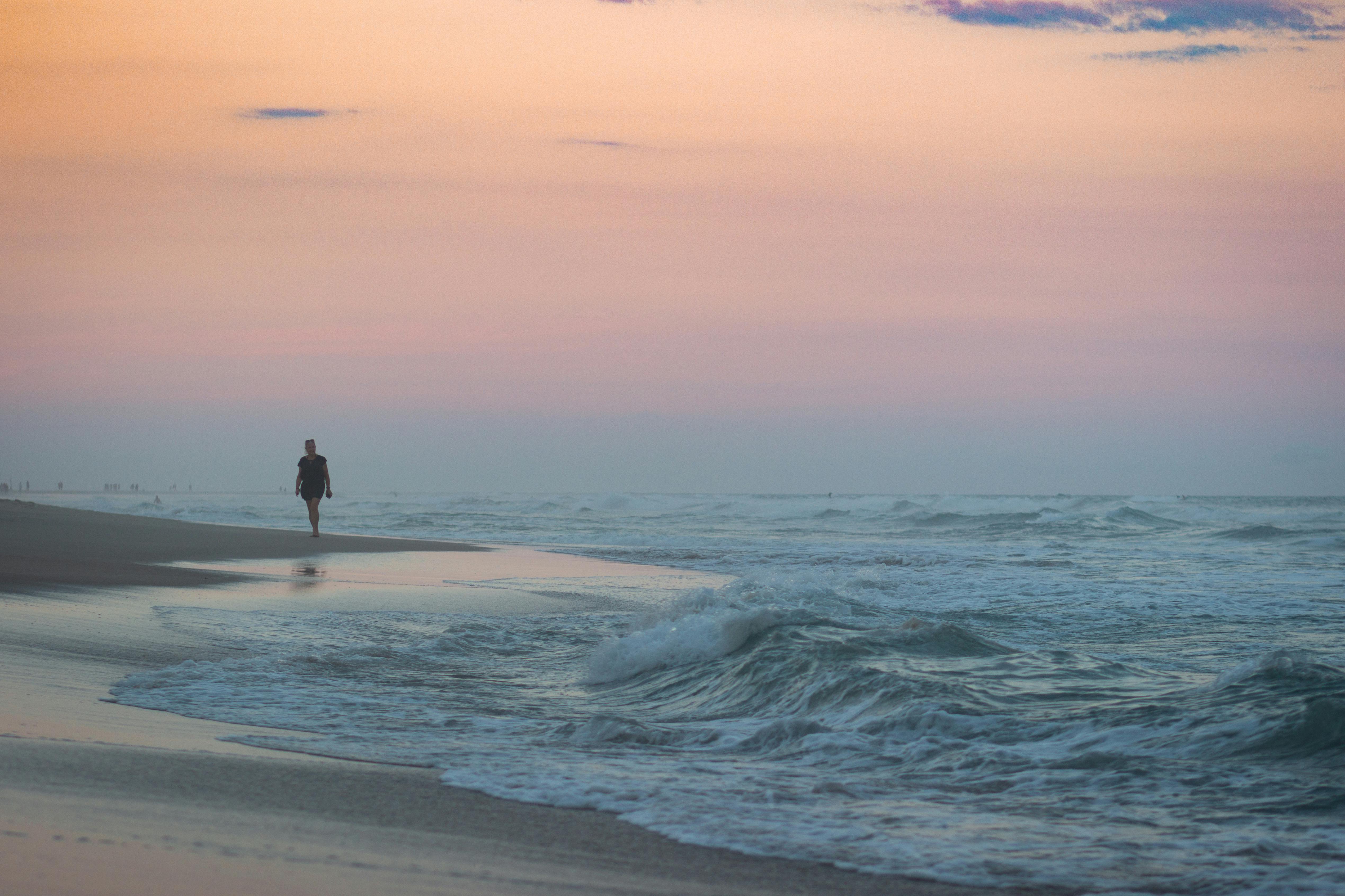 A Person Walking on the Beach Shore · Free Stock Photo
