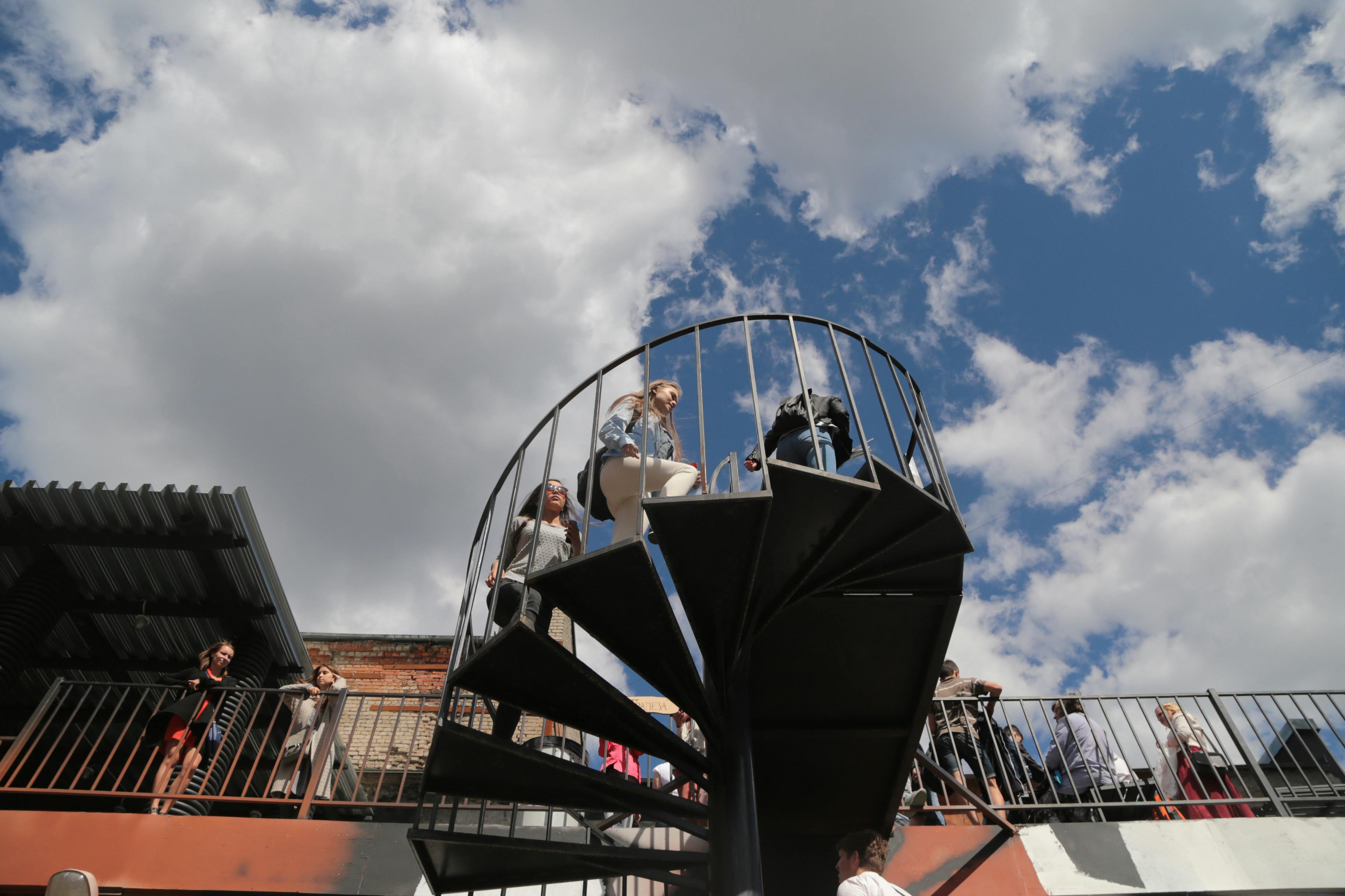 People on spiral staircase near building with terrace · Free Stock Photo