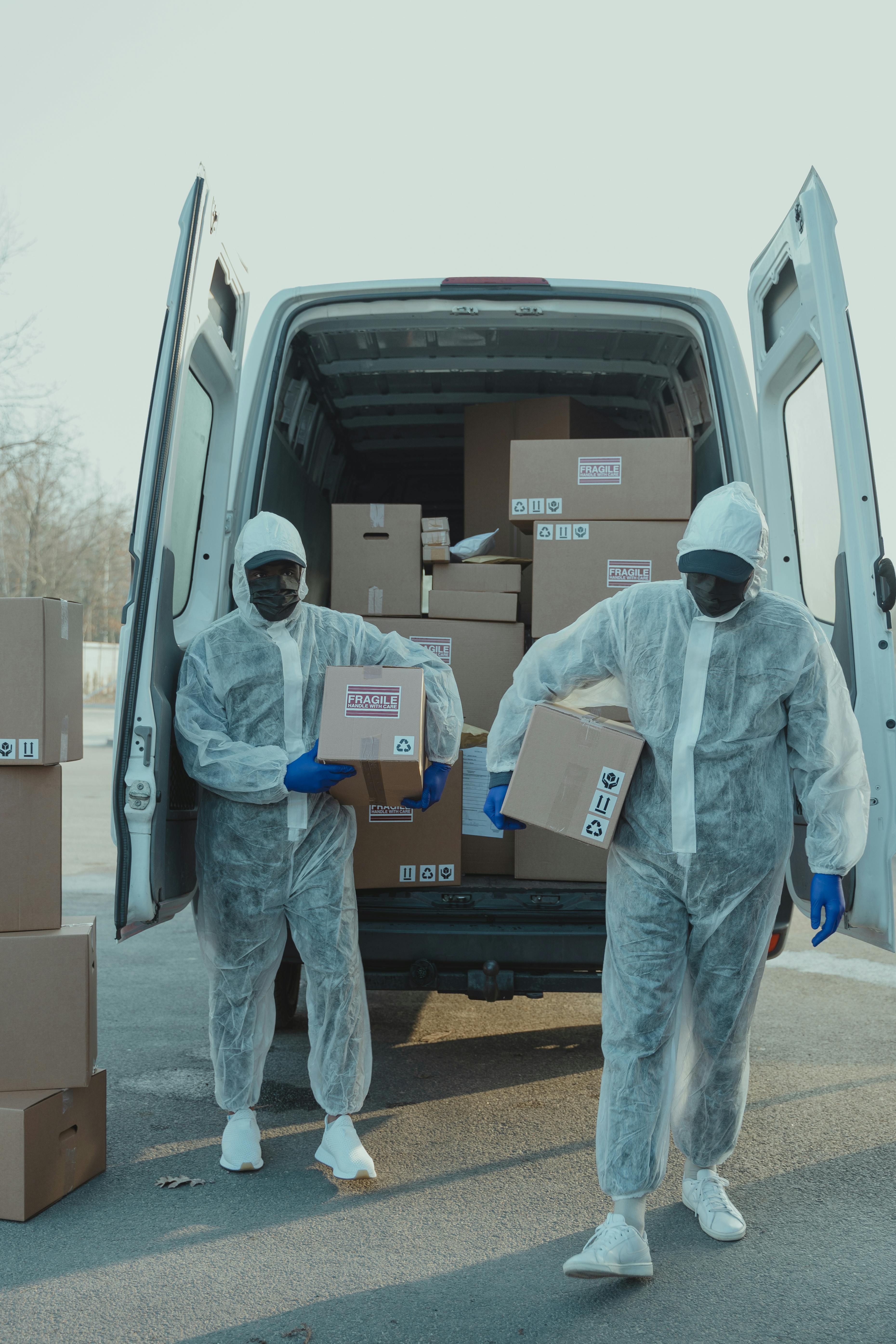 Two Delivery Men in PPE carrying a Box · Free Stock Photo