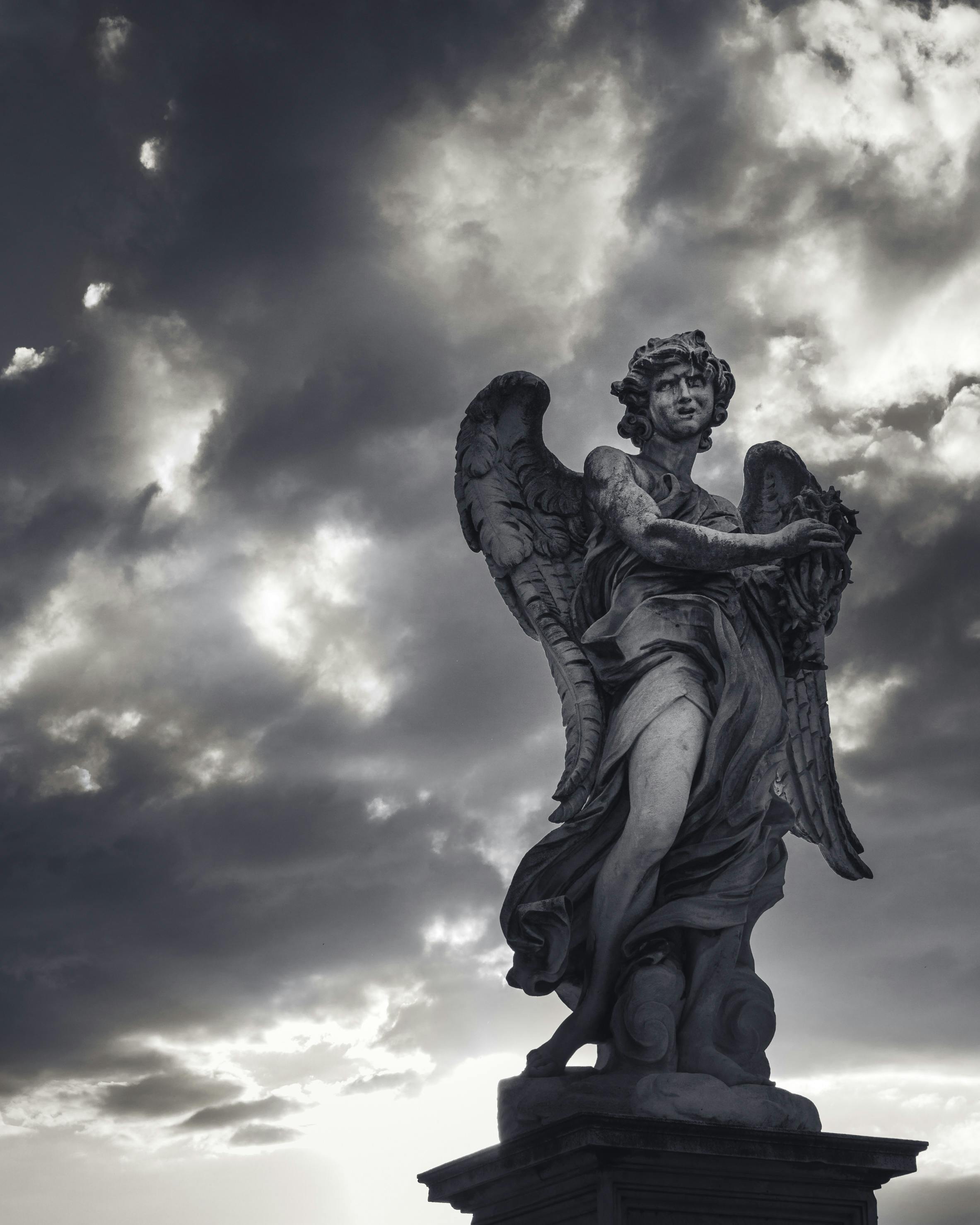 Grayscale Photography of Angel Statue Under Cloudy Skies · Free Stock Photo