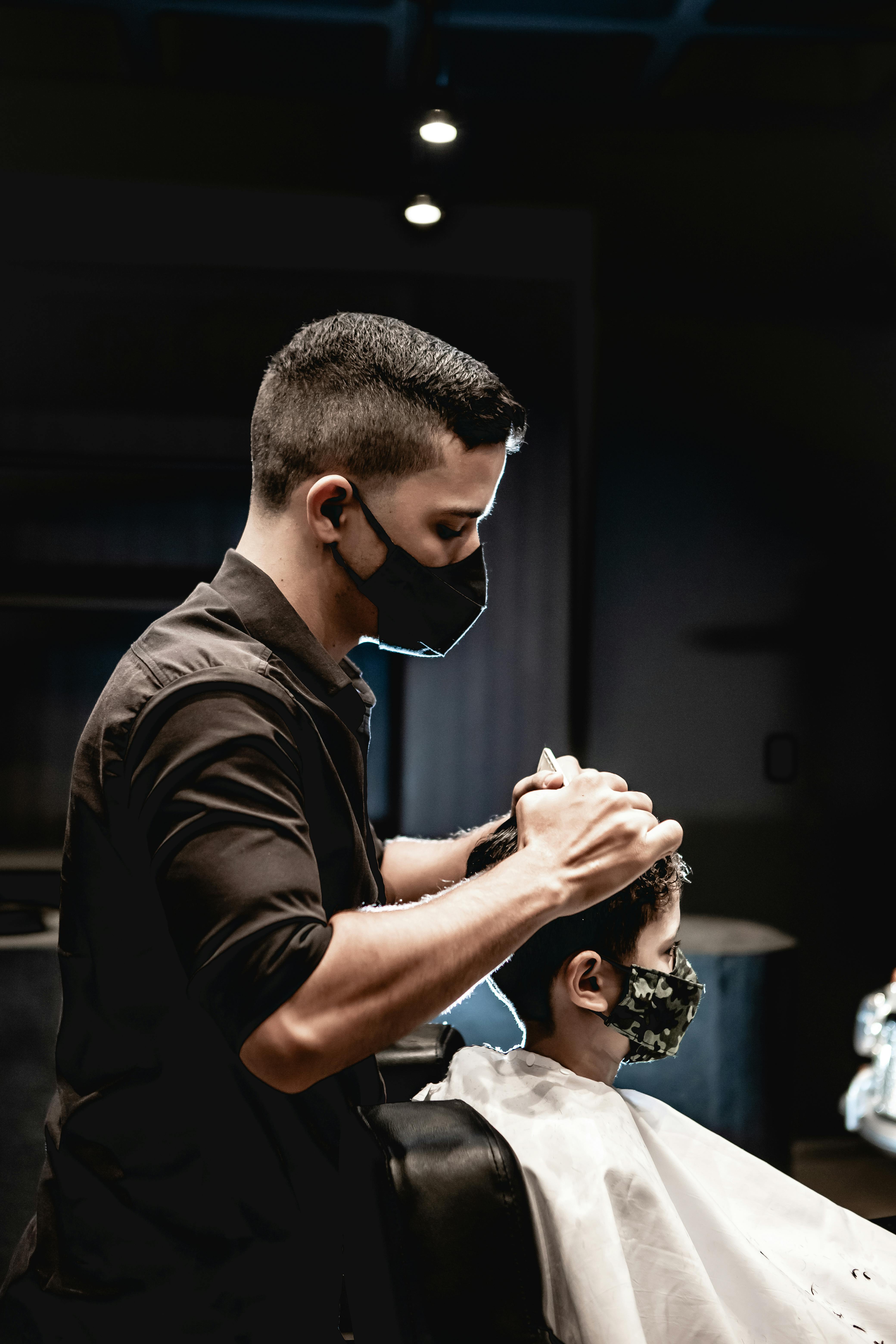 A Barber Trimming the Hair of a Smoking Client · Free Stock Photo