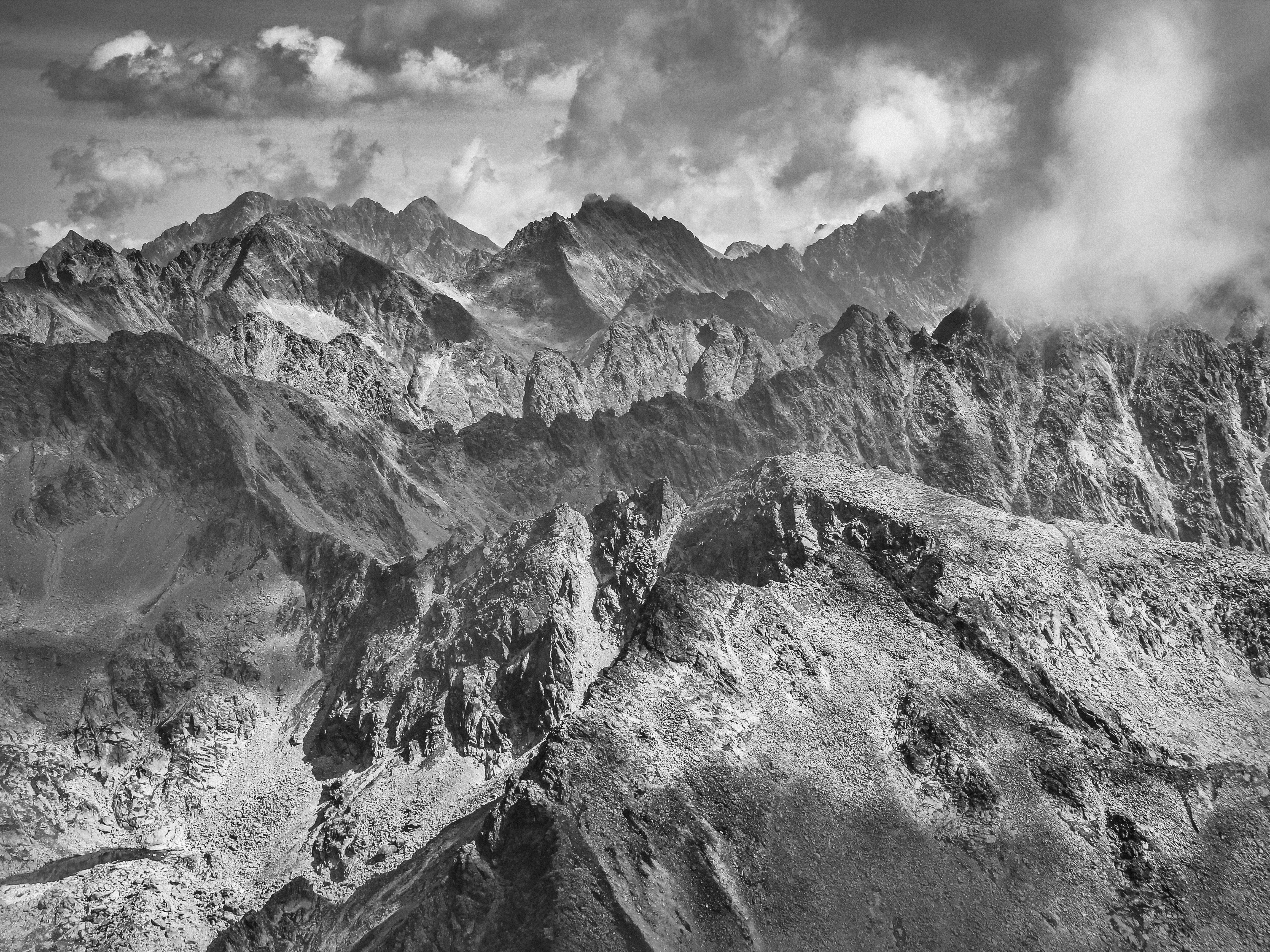 Grayscale Photo of Mountain Ranges Under Cloudy Sky · Free Stock Photo