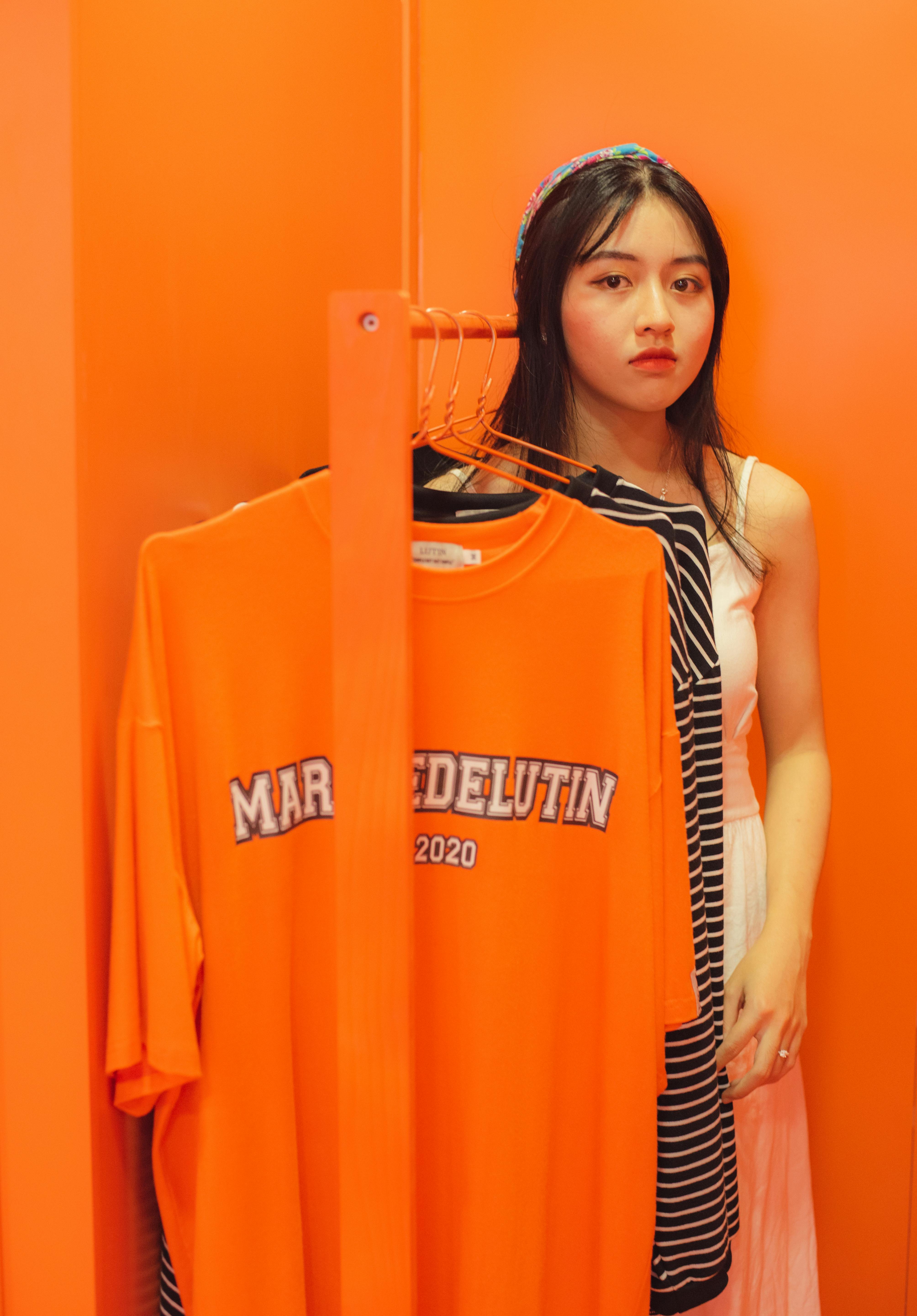 Teenage Girl Standing Beside Clothing Rack · Free Stock Photo