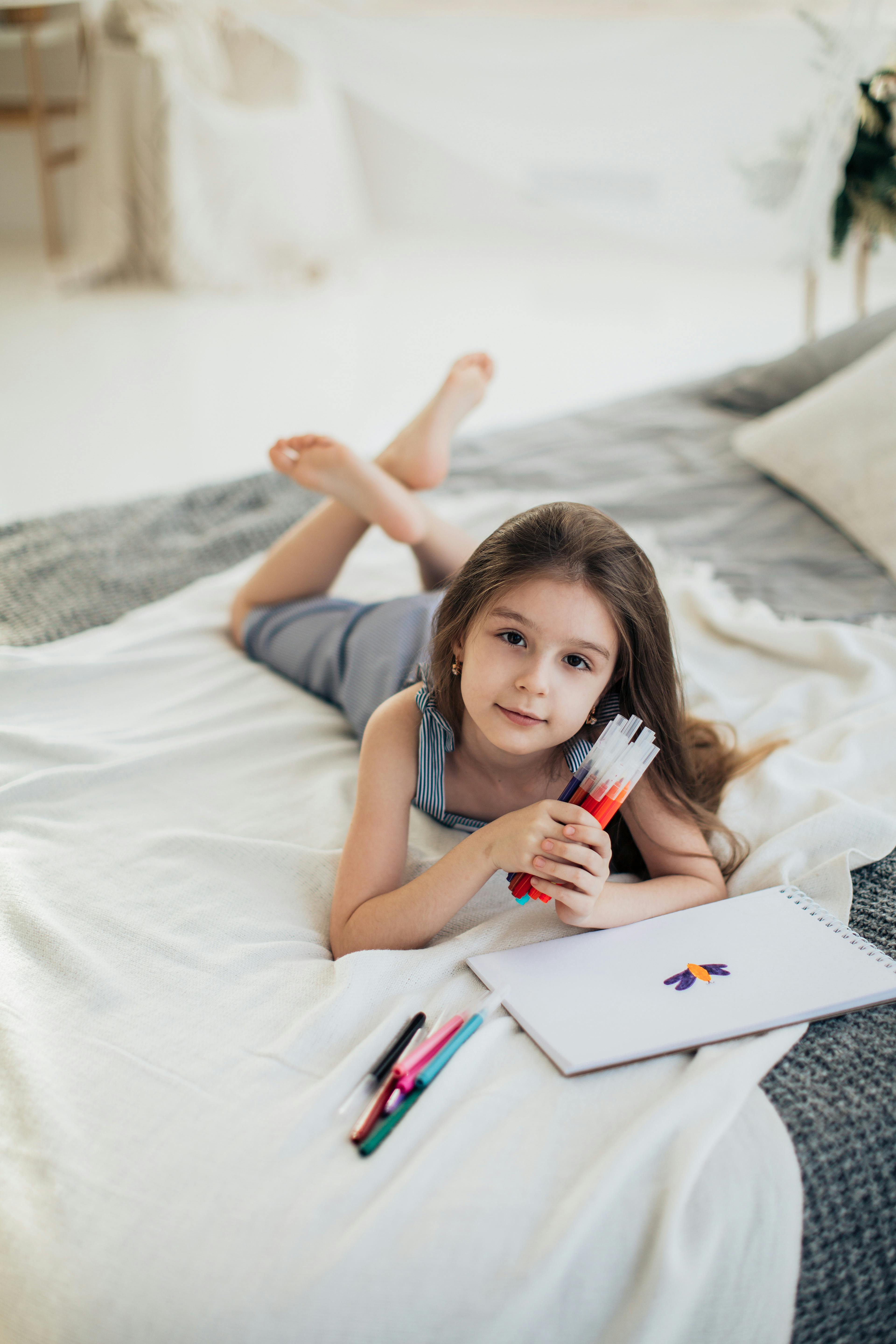 Girl Holding Markers on a Bed · Free Stock Photo