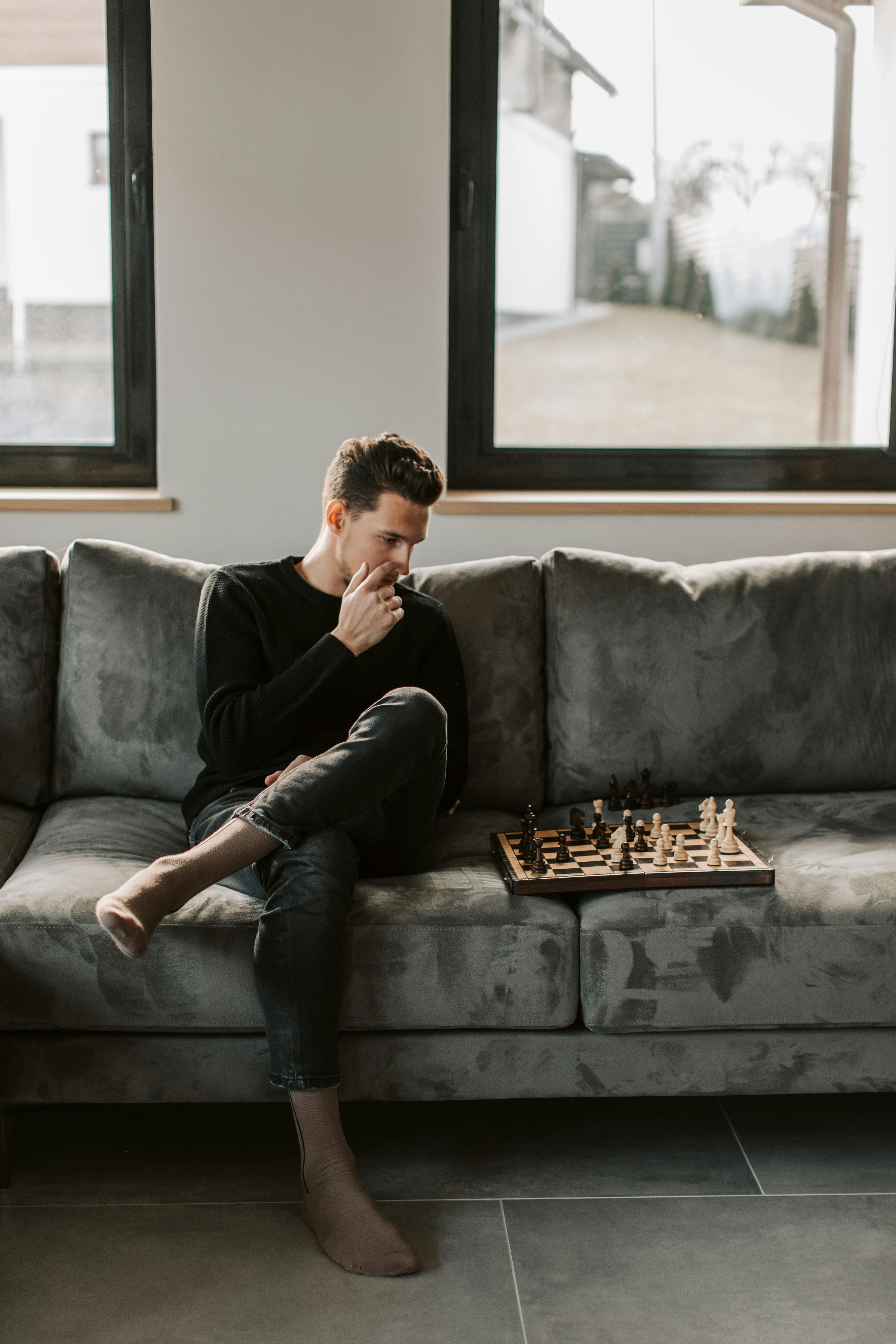 A Man Playing Chess on the Couch · Free Stock Photo
