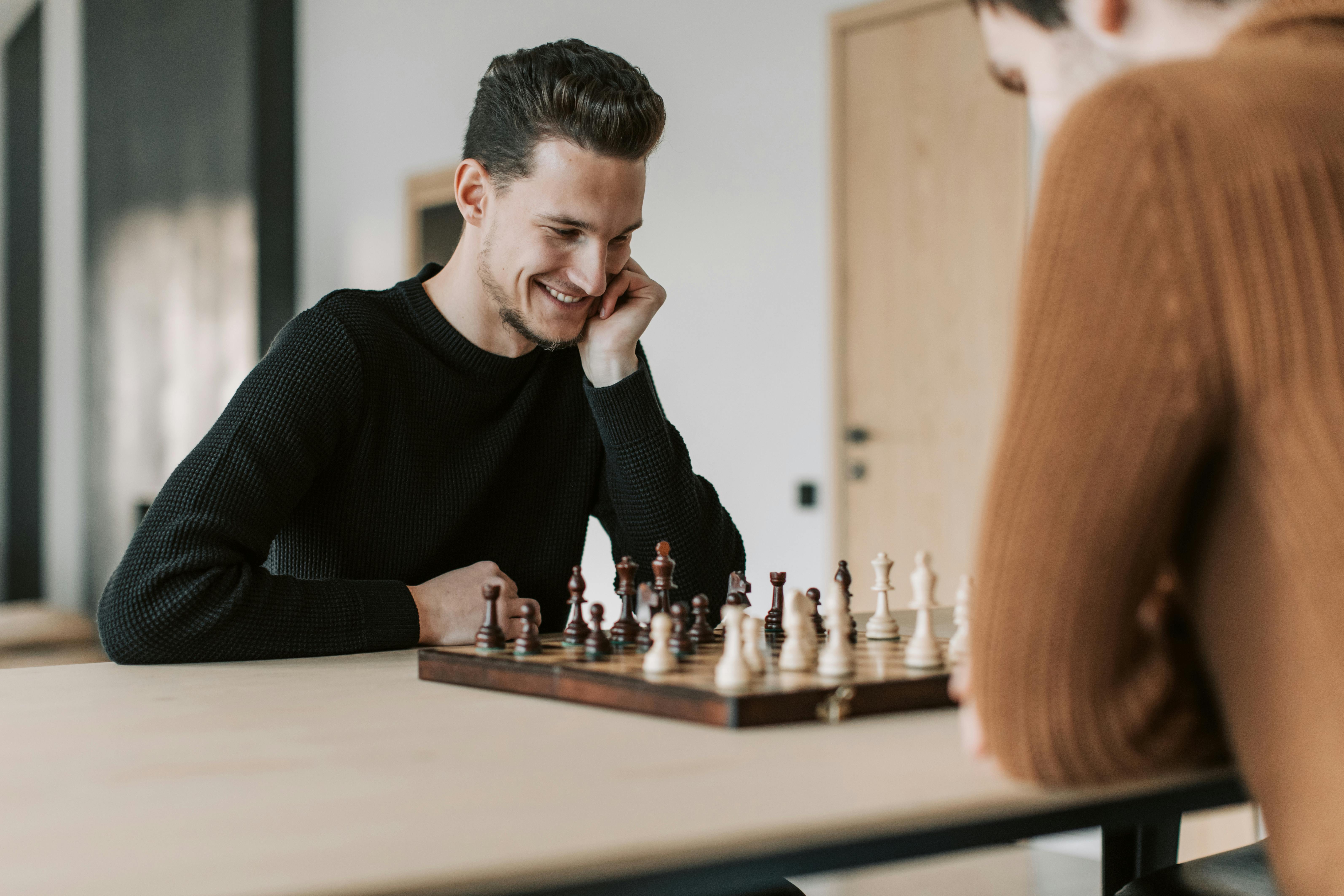Man in Black Sweater Sitting by the Table Playing Chess · Free Stock Photo