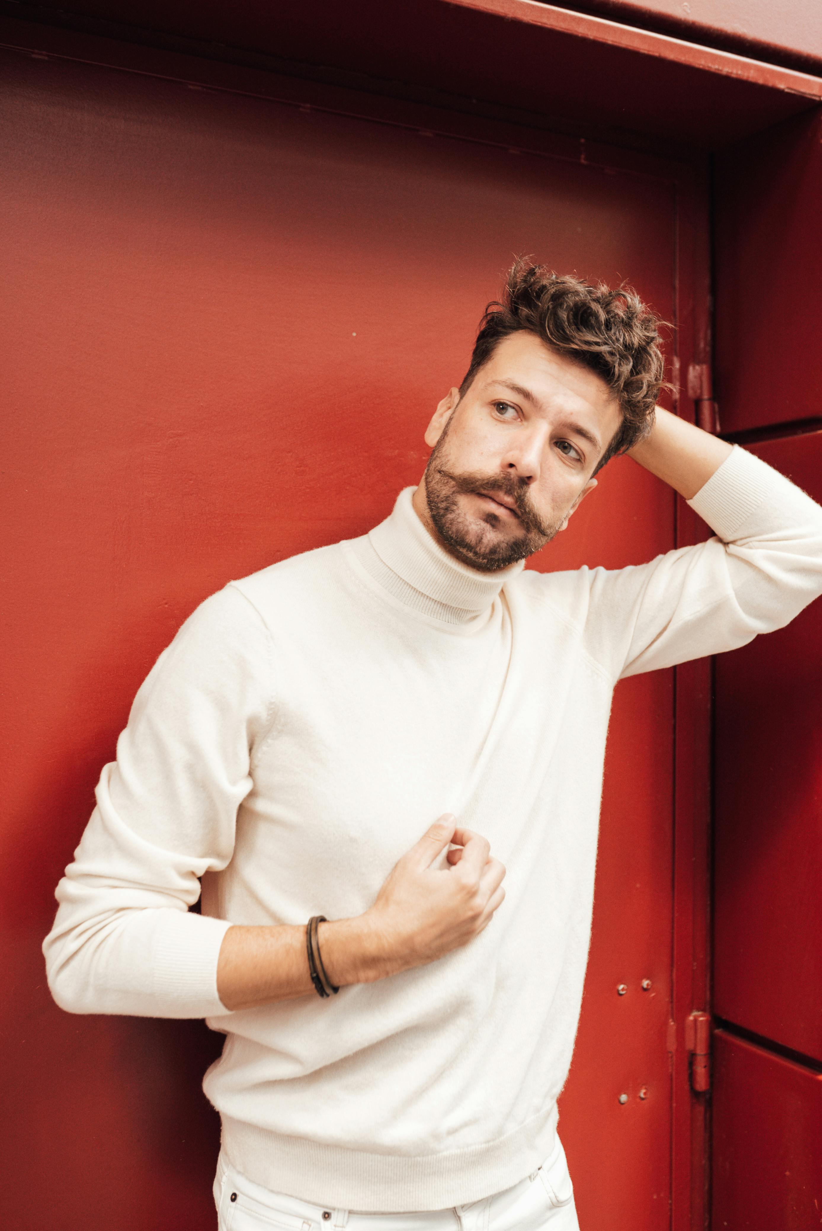 Wistful man leaning on door of red building · Free Stock Photo