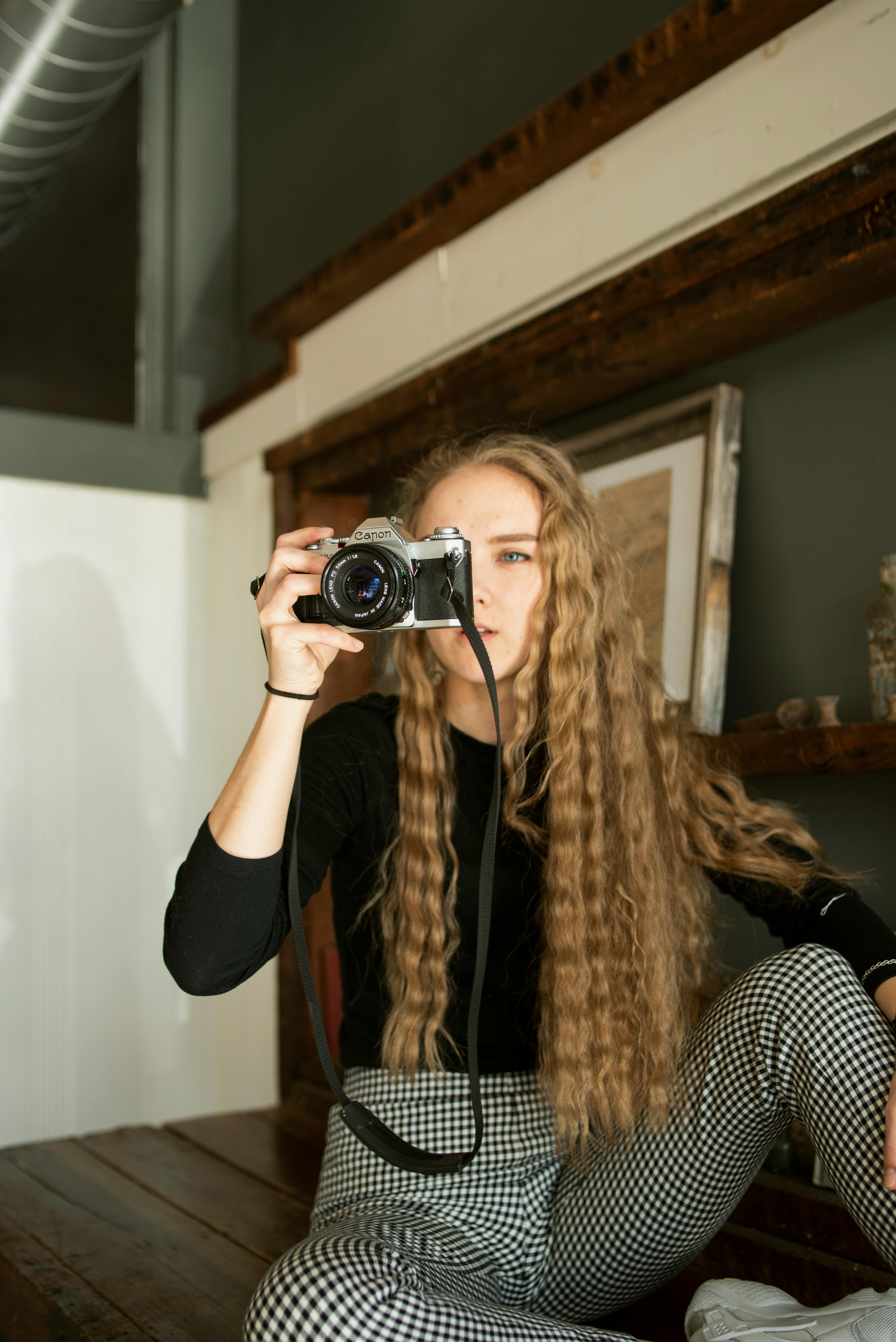 Woman with Blonde Hair Holding a Camera while Sitting · Free Stock Photo