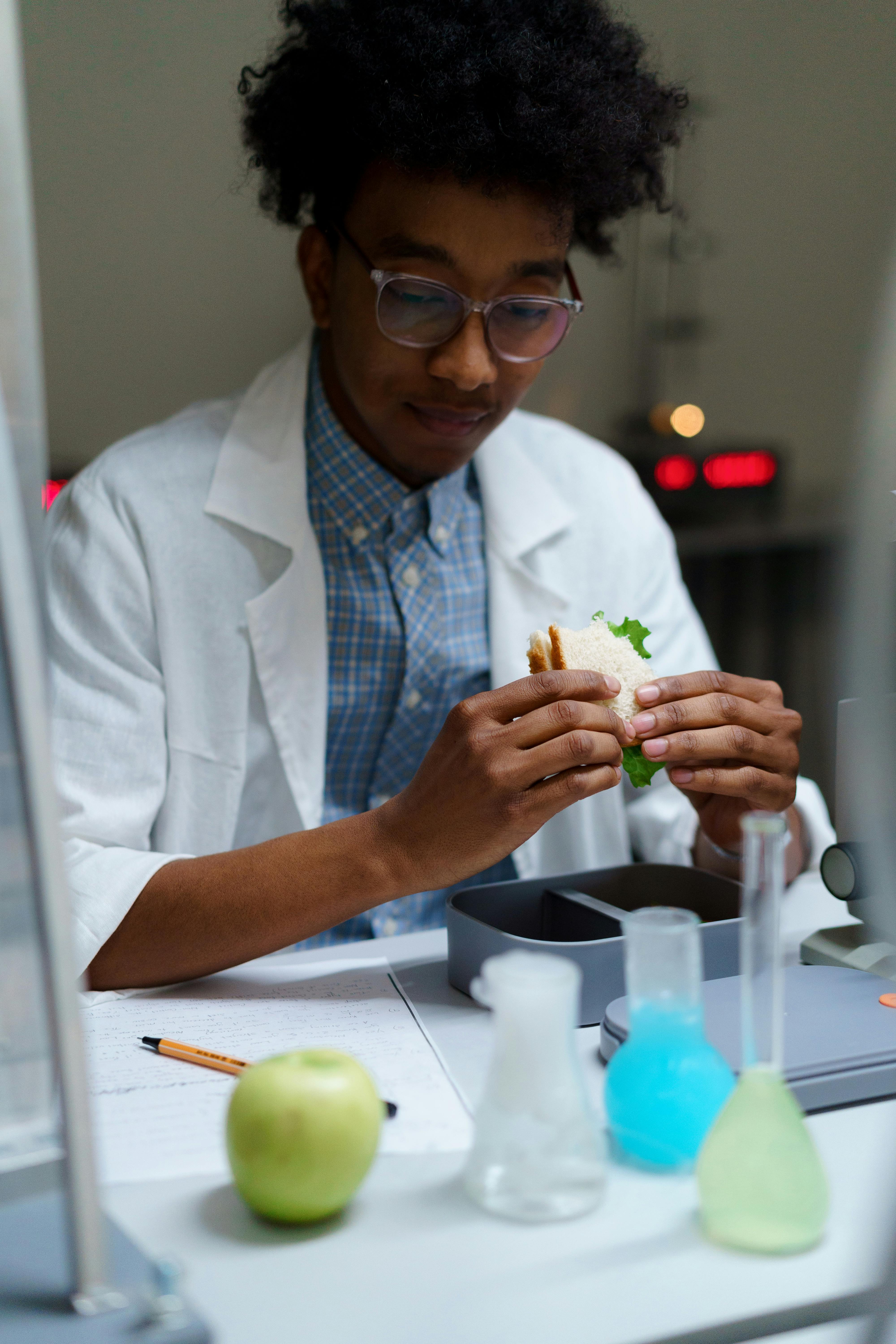 Man Eating Sandwich While Doing An Experiment · Free Stock Photo