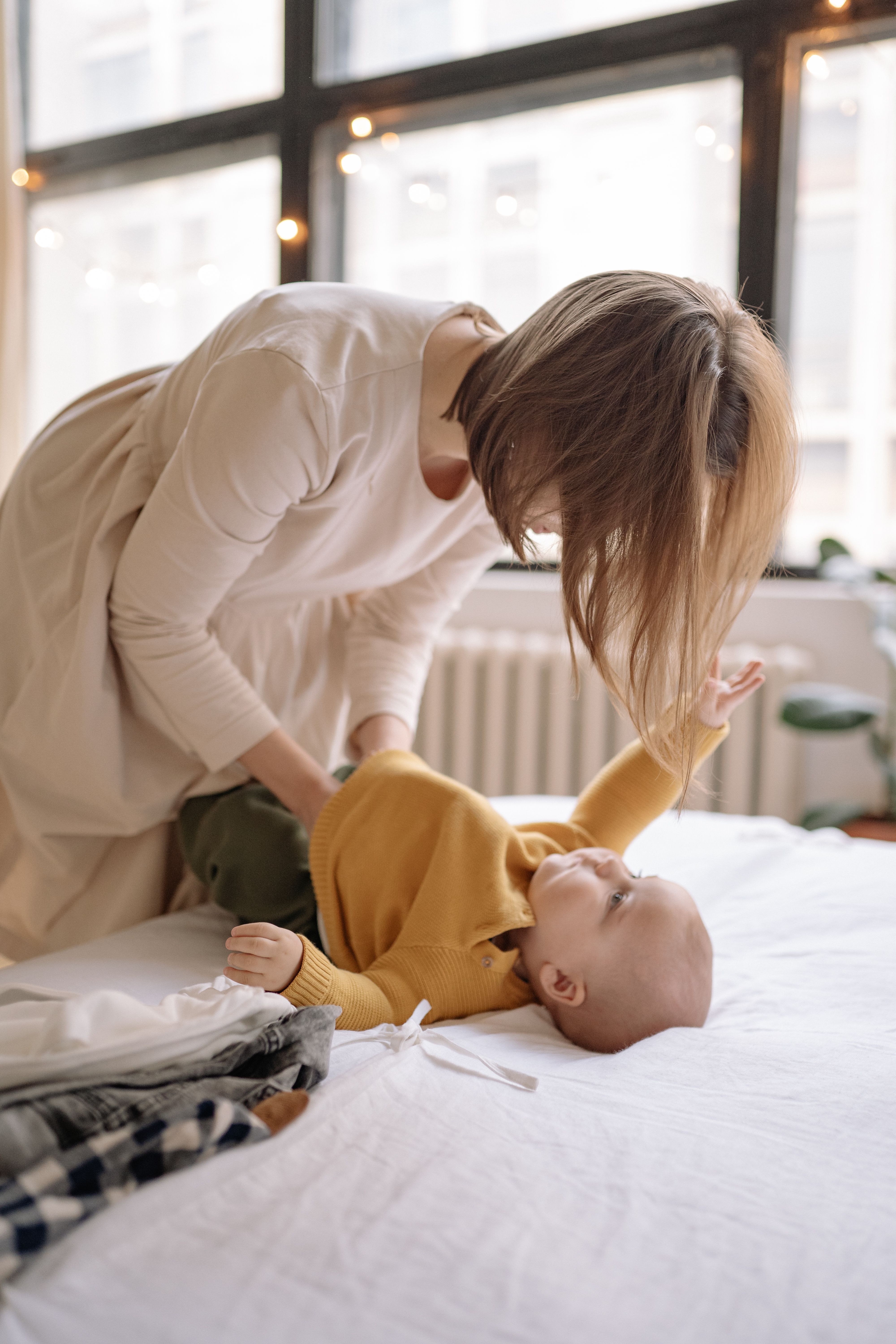A Mother Taking Off Her Baby's Yellow Sweater · Free Stock Photo