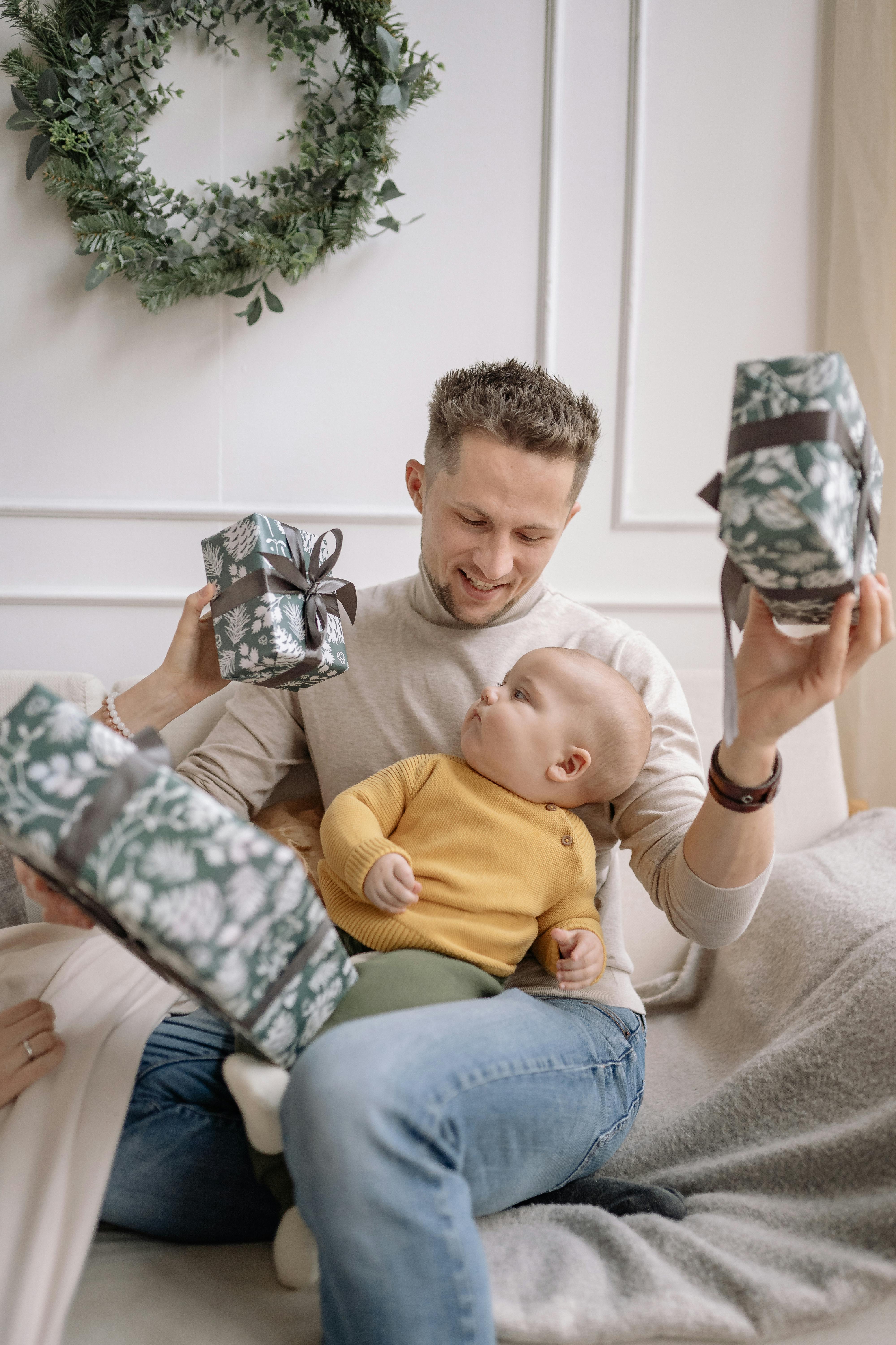 Father Sitting with His Newborn Baby on His Lap and Holding Christmas ...