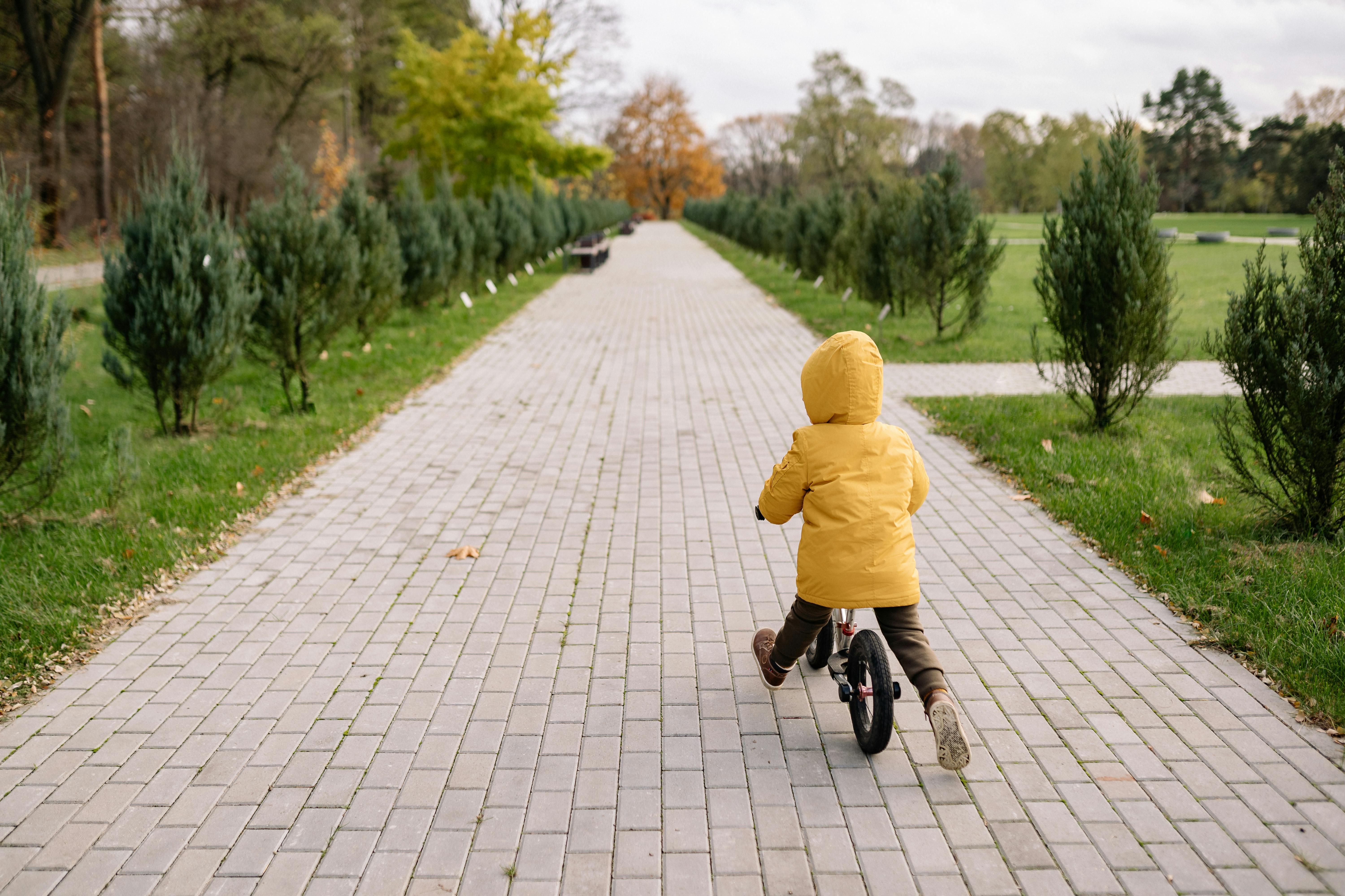 Anonymous kid in helmet riding run bike on pavement in countryside ...