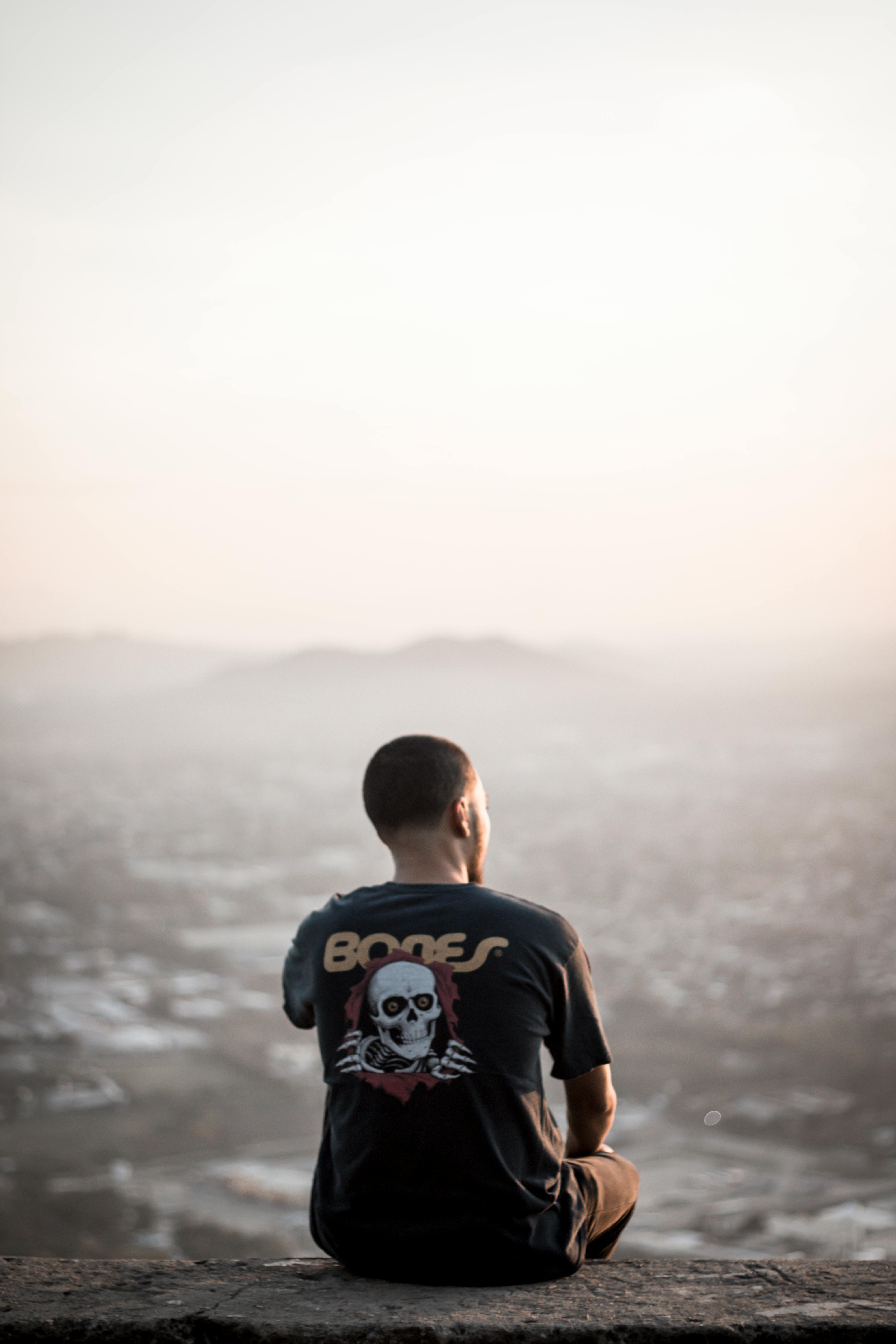 Back View of a Person Sitting on a Concrete Surface · Free Stock Photo