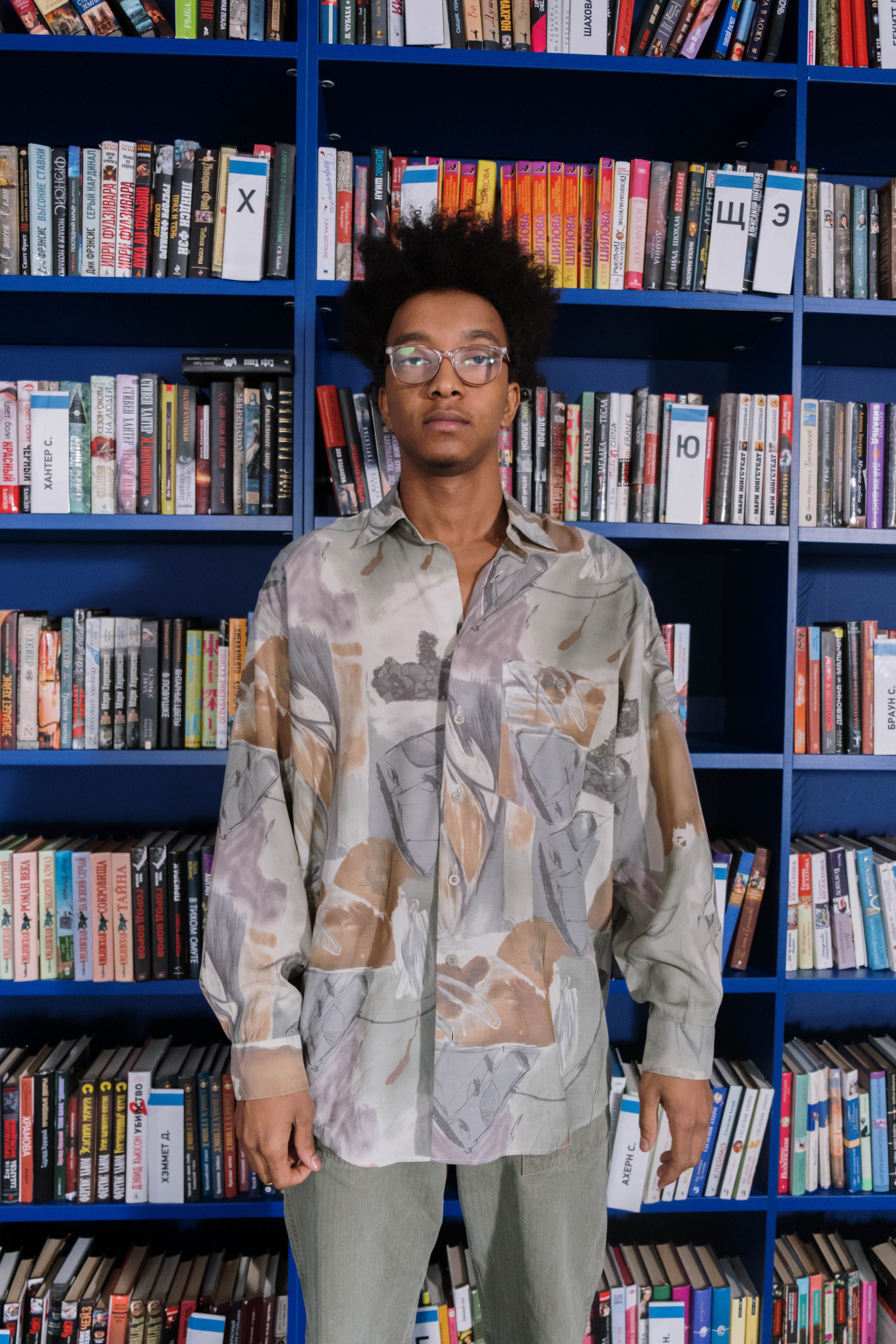 A Male Teenager Standing near the Bookcase · Free Stock Photo