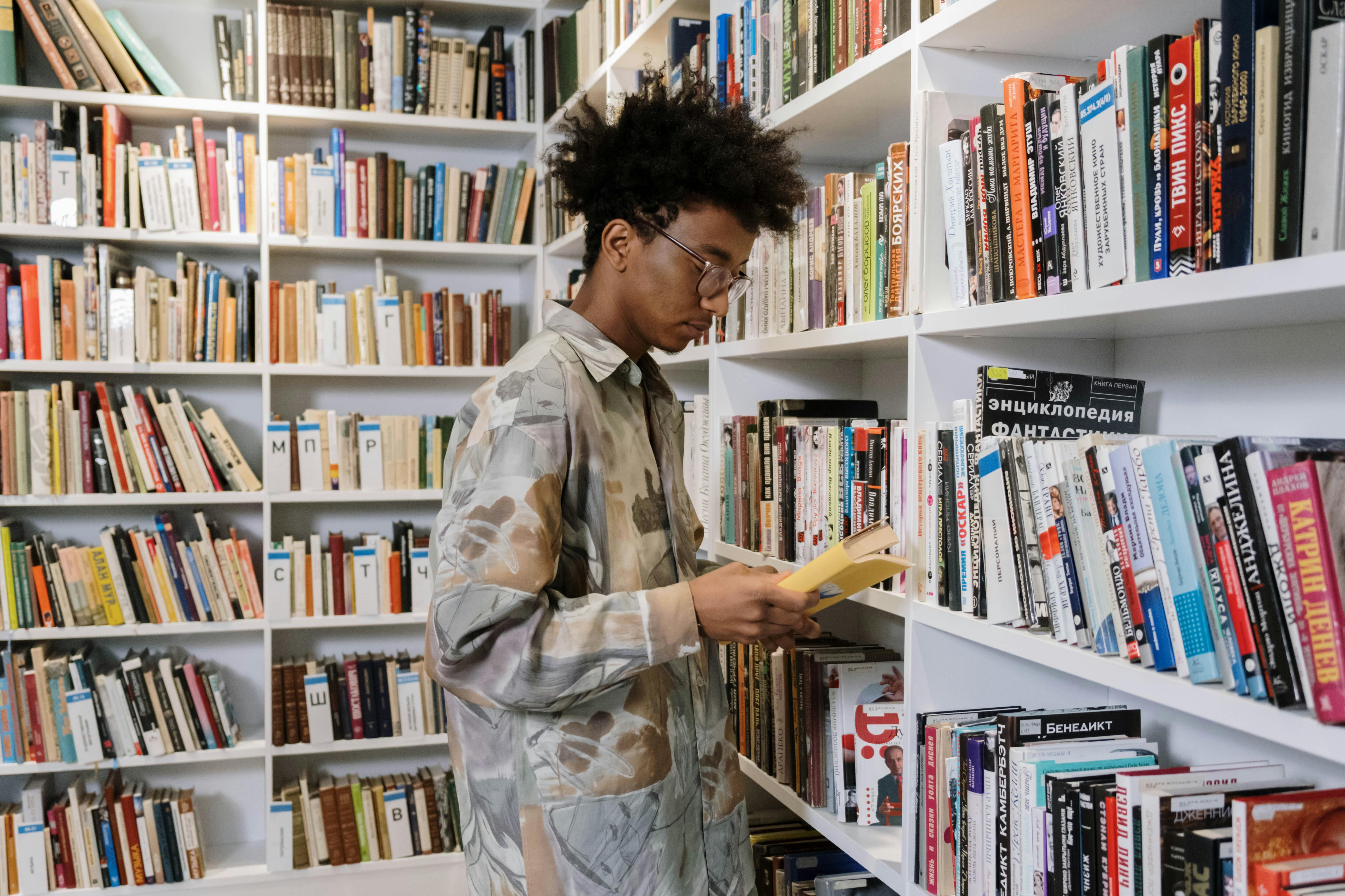 An Afro-Haired Man Reading a Book in the Library · Free Stock Photo