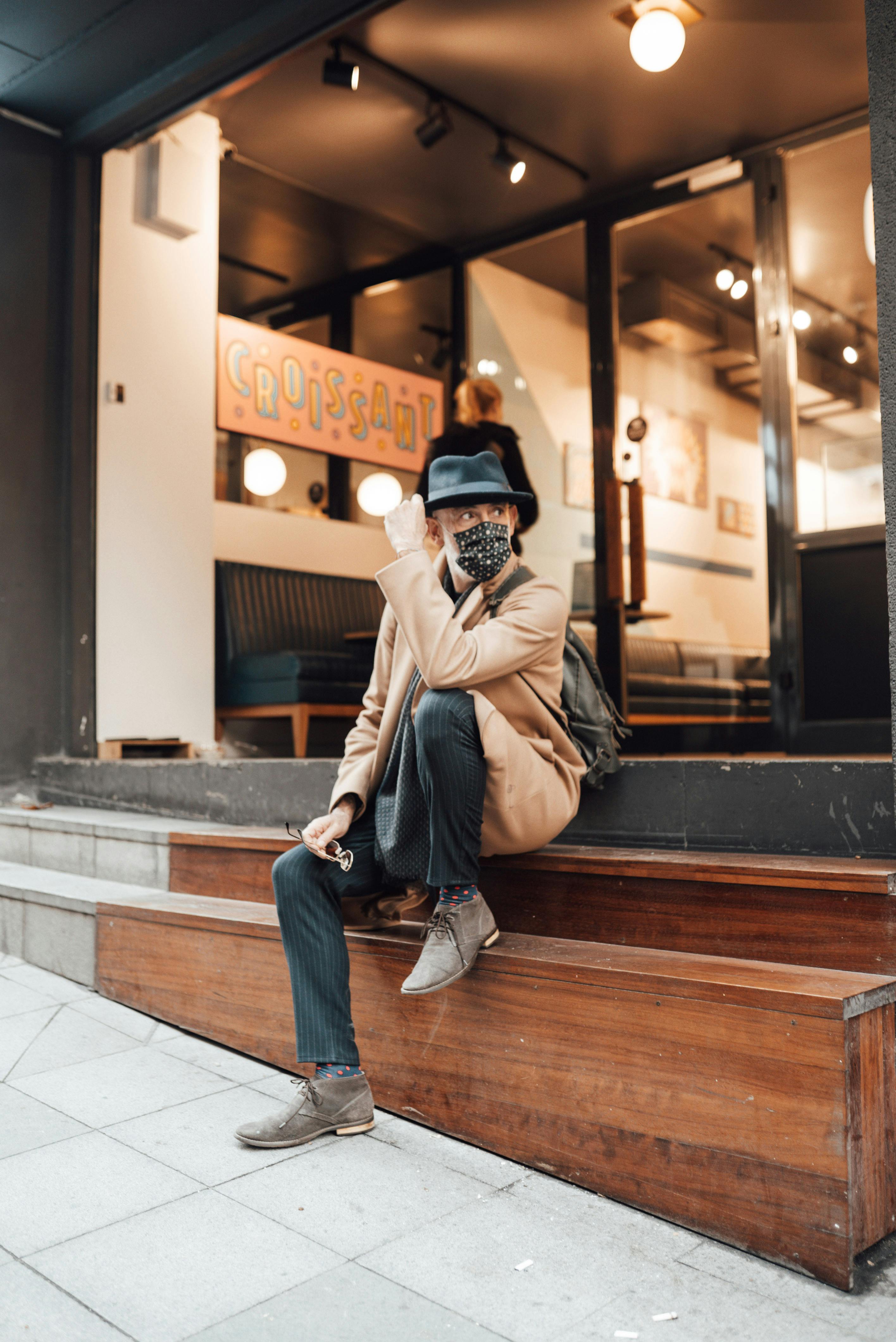 Stylish man in mask sitting on steps · Free Stock Photo