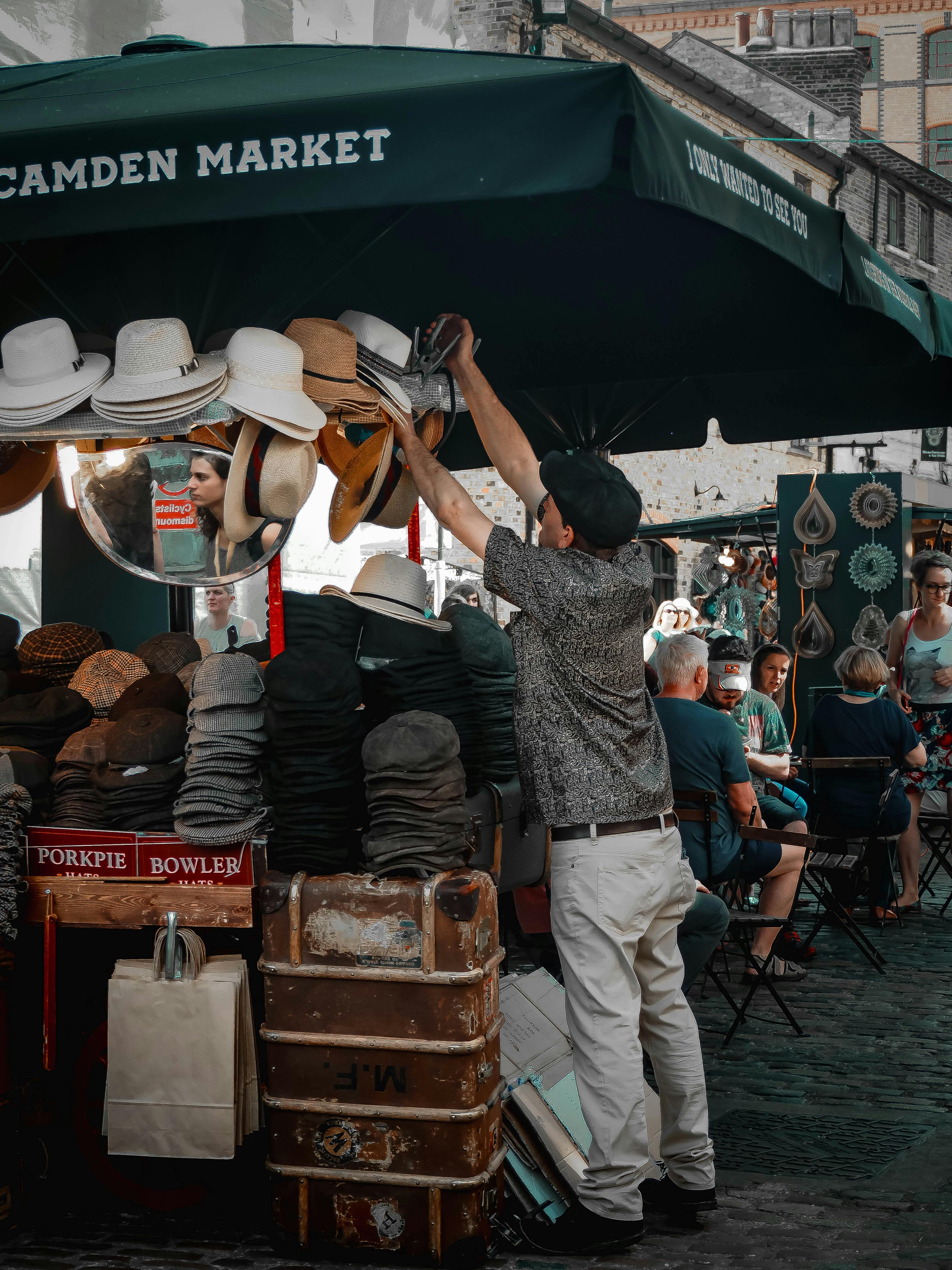 A Hat Vendor Arranging His Wares · Free Stock Photo