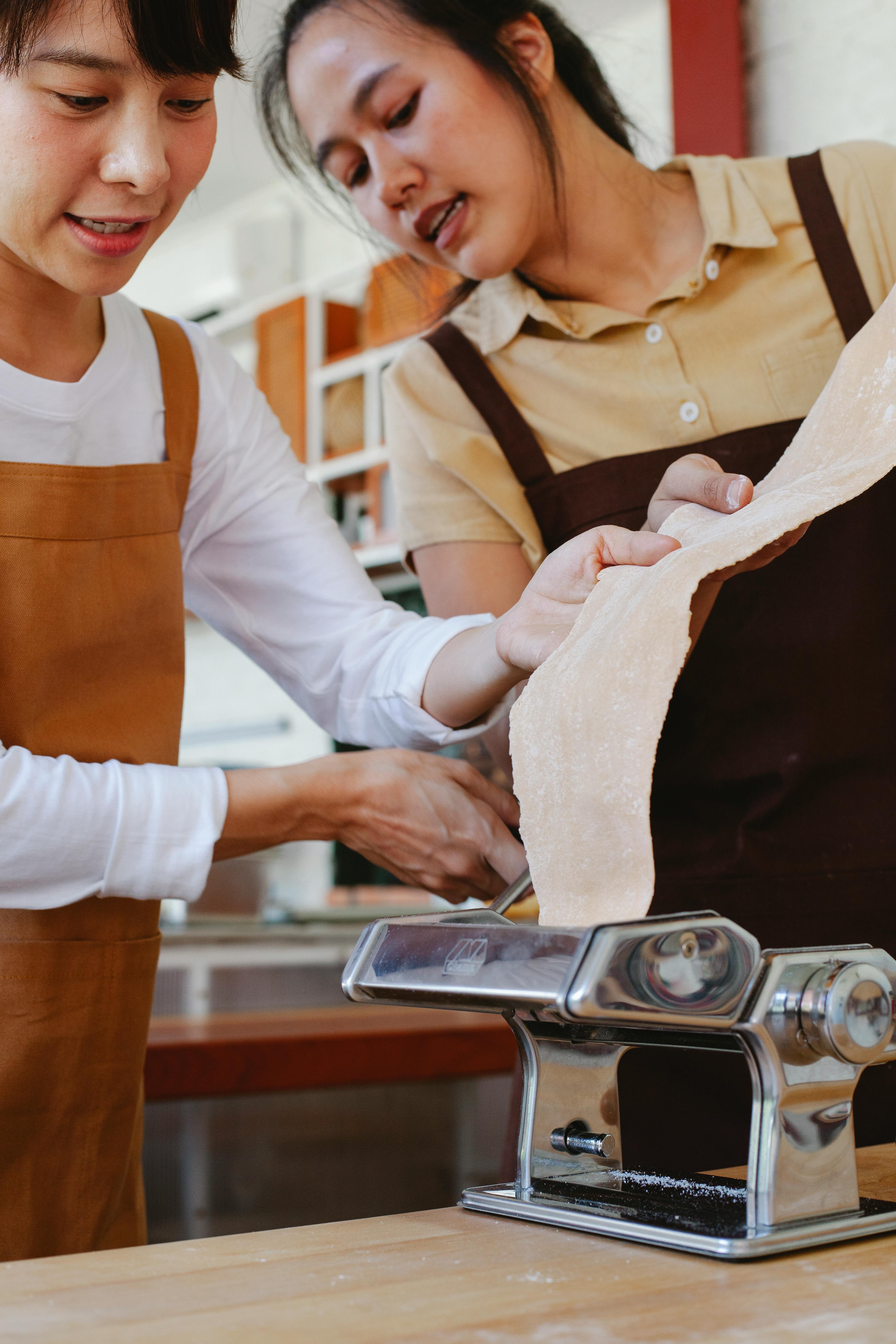 Women Putting Dough in a Pasta Maker · Free Stock Photo