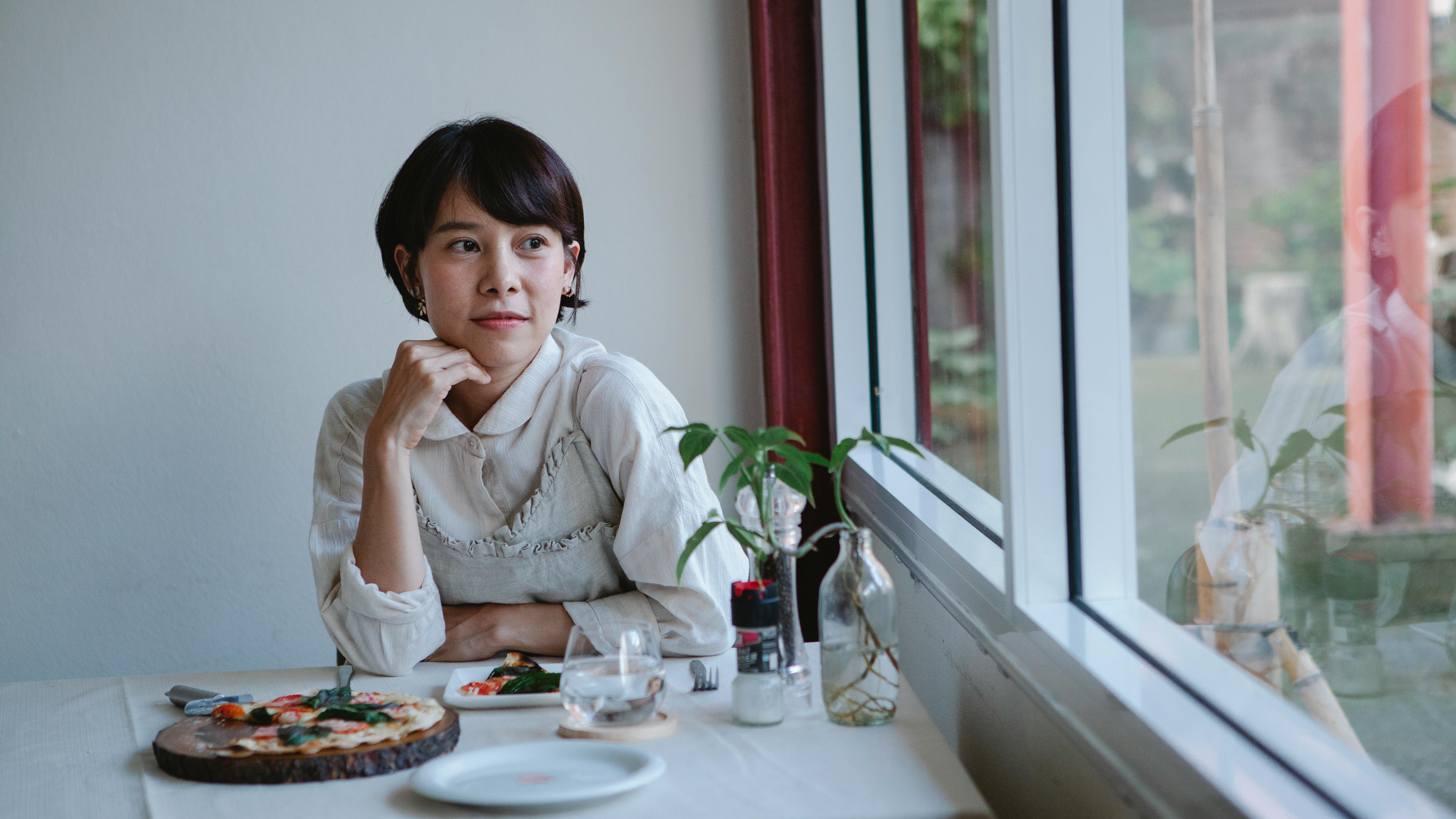 Woman Sitting Behind the Table with Pizza on Her Plate and Looking Out ...