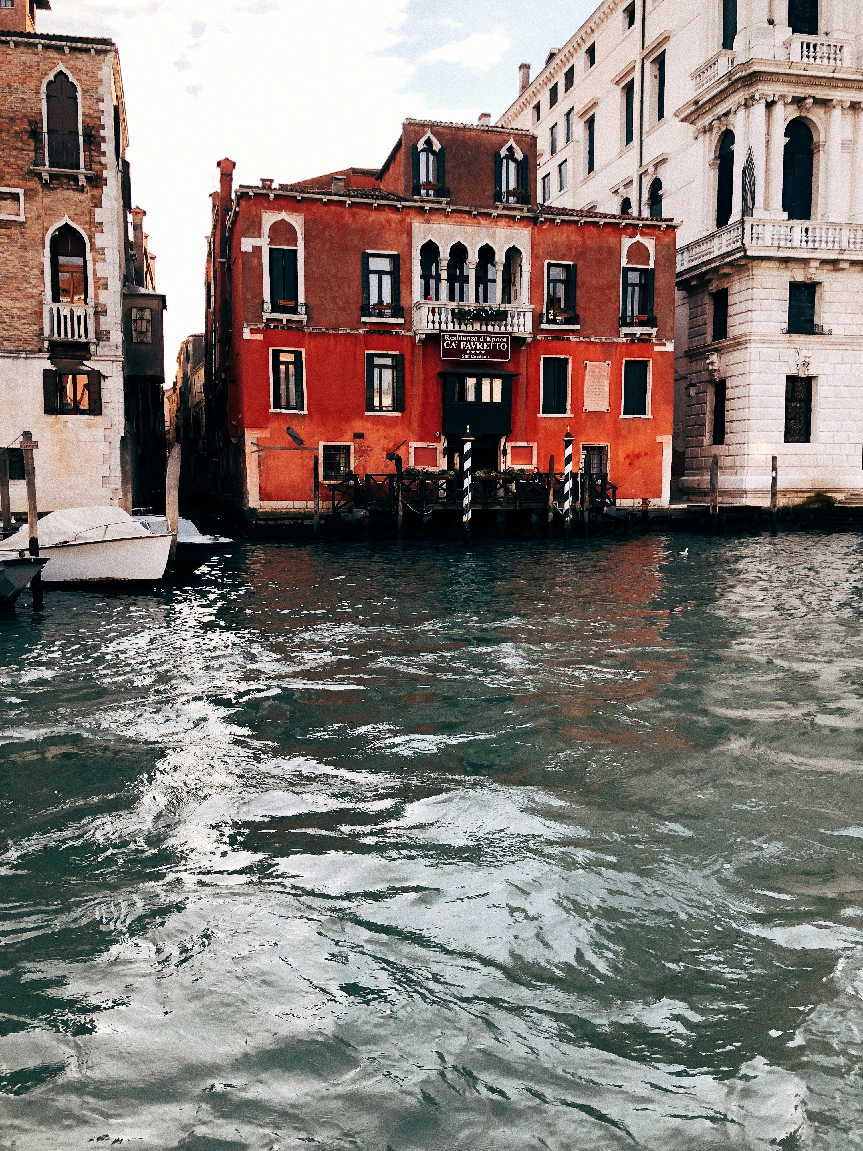 Red Building Between Brick Building Floating on a Body of Water · Free ...