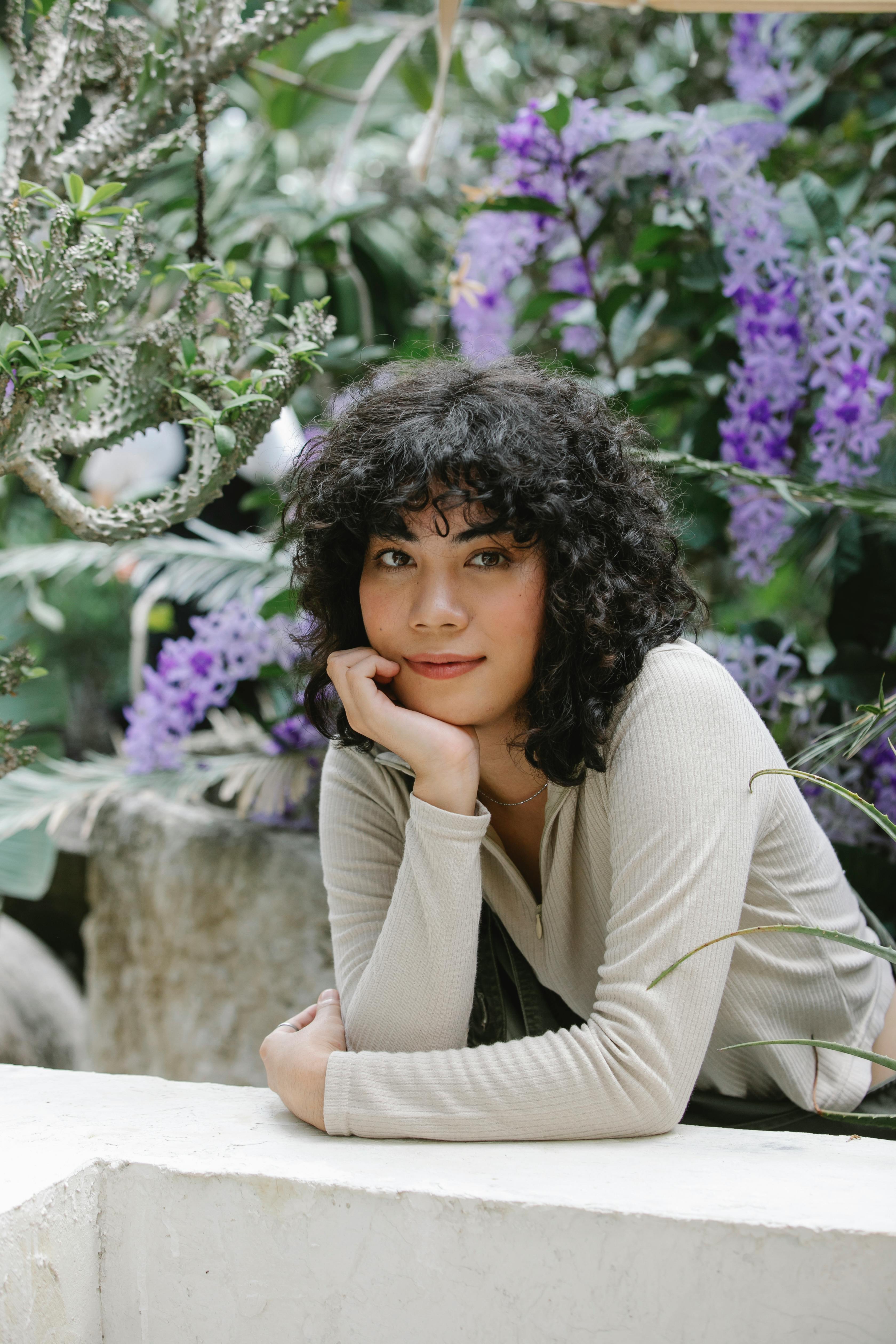 Smiling ethnic woman leaning on hand in blooming garden · Free Stock Photo