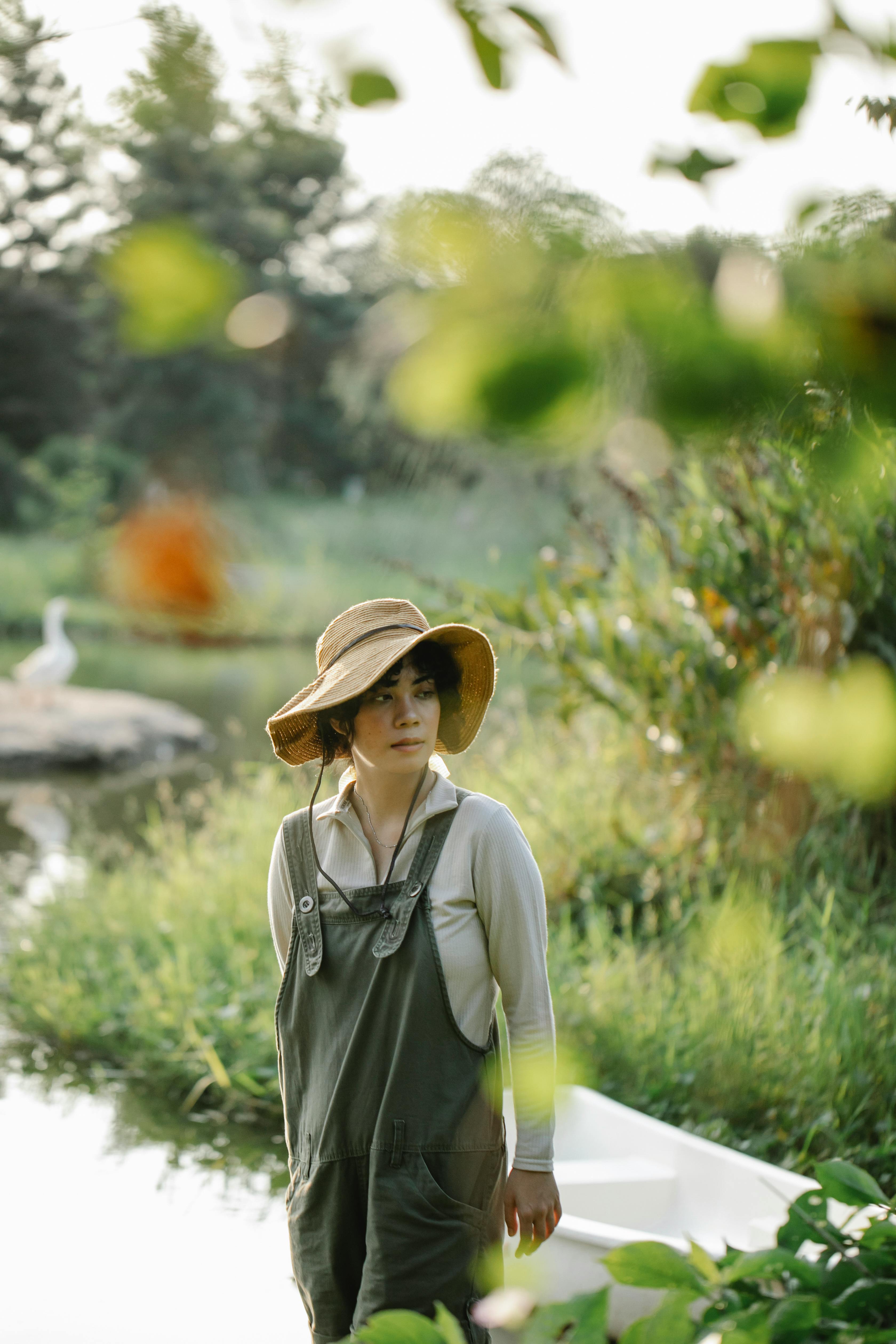 Contemplative ethnic farmer against pond and green trees · Free Stock Photo