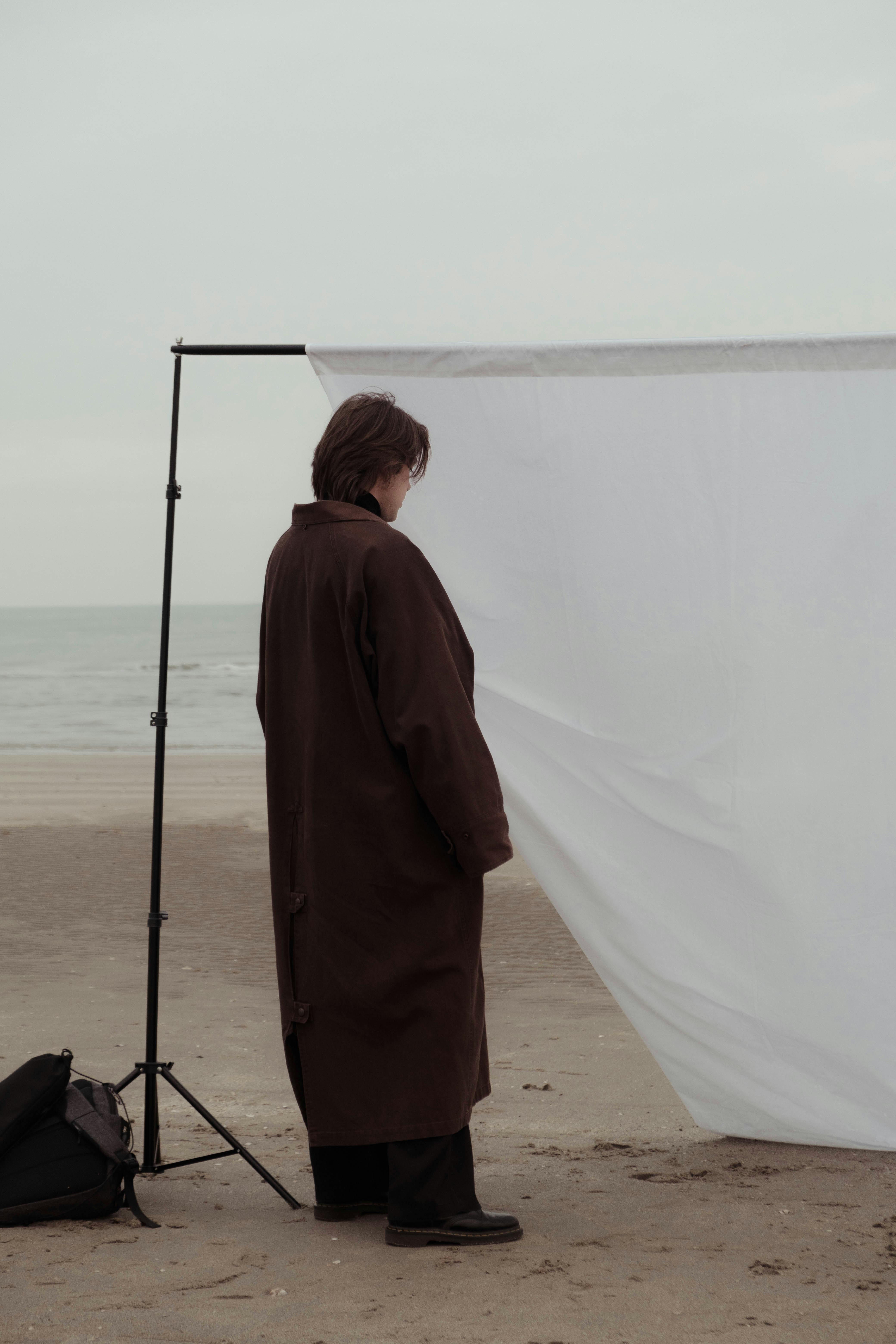 Stylish man model standing on sandy coast near sea · Free Stock Photo