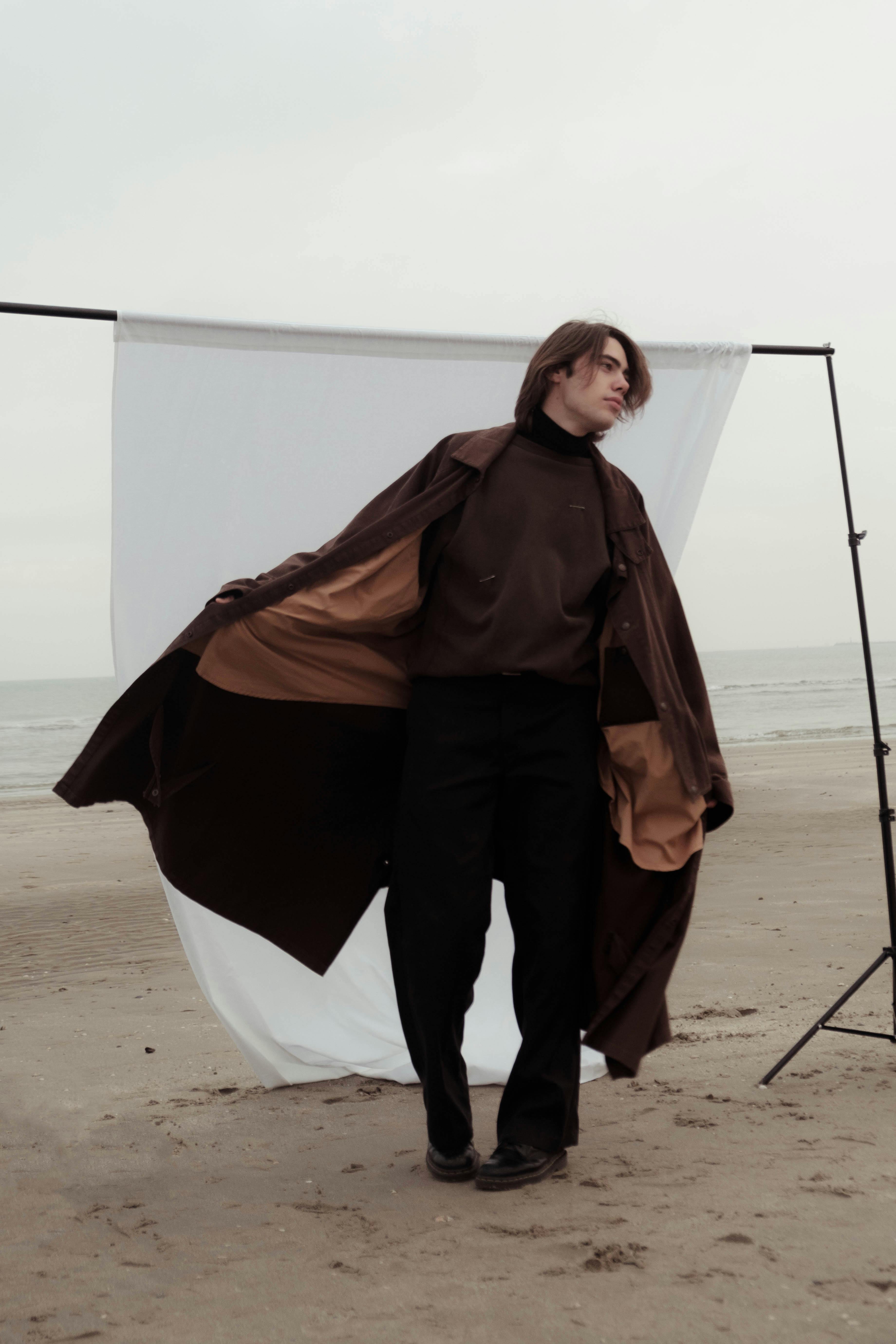 Stylish man model standing on sandy coast near sea · Free Stock Photo