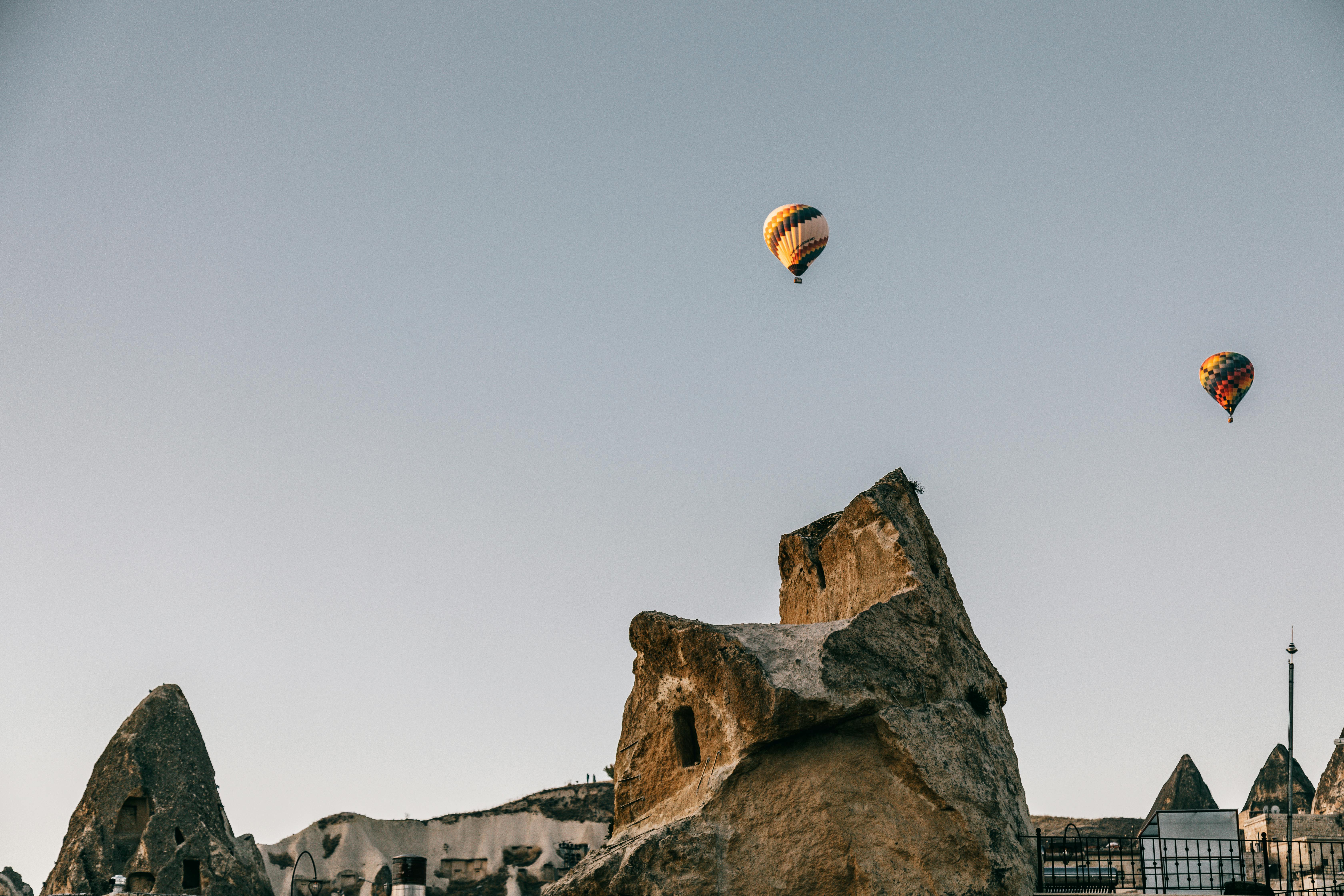Colorful air balloons racing over rocky formation in daylight · Free ...