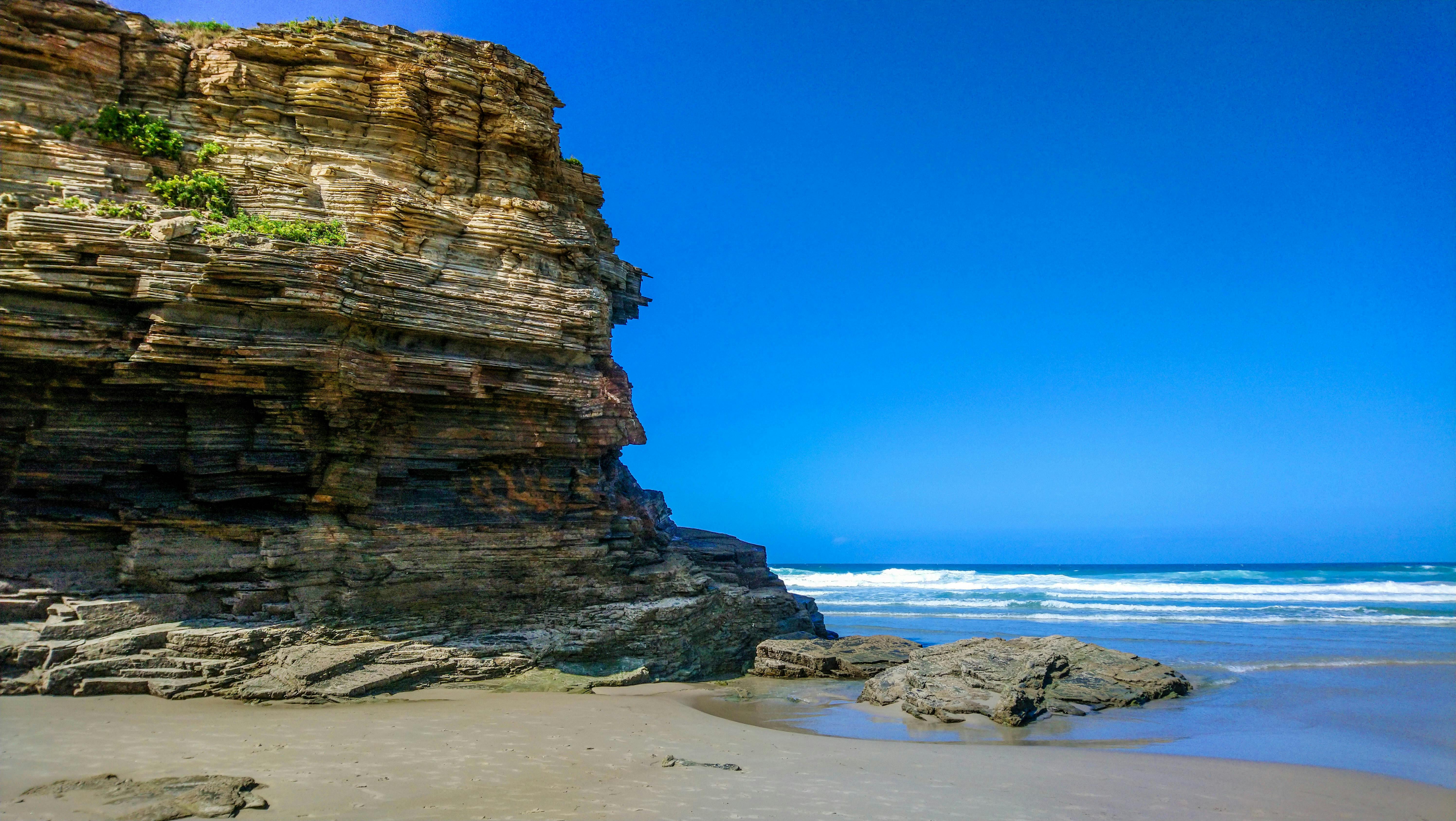 Photo of a Beach with a Cliff and Rocks · Free Stock Photo