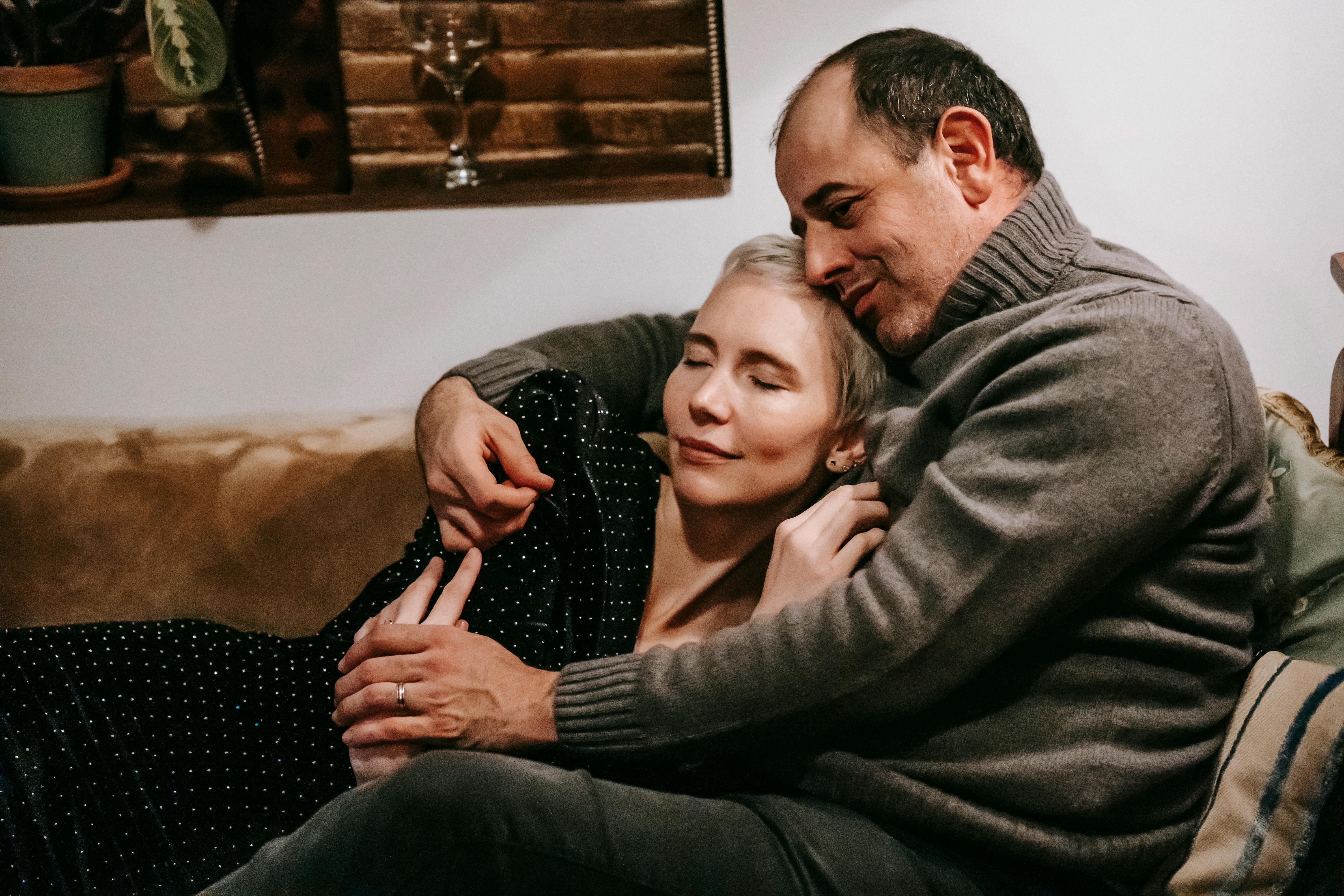 Loving couple cuddling tenderly sitting on sofa · Free Stock Photo