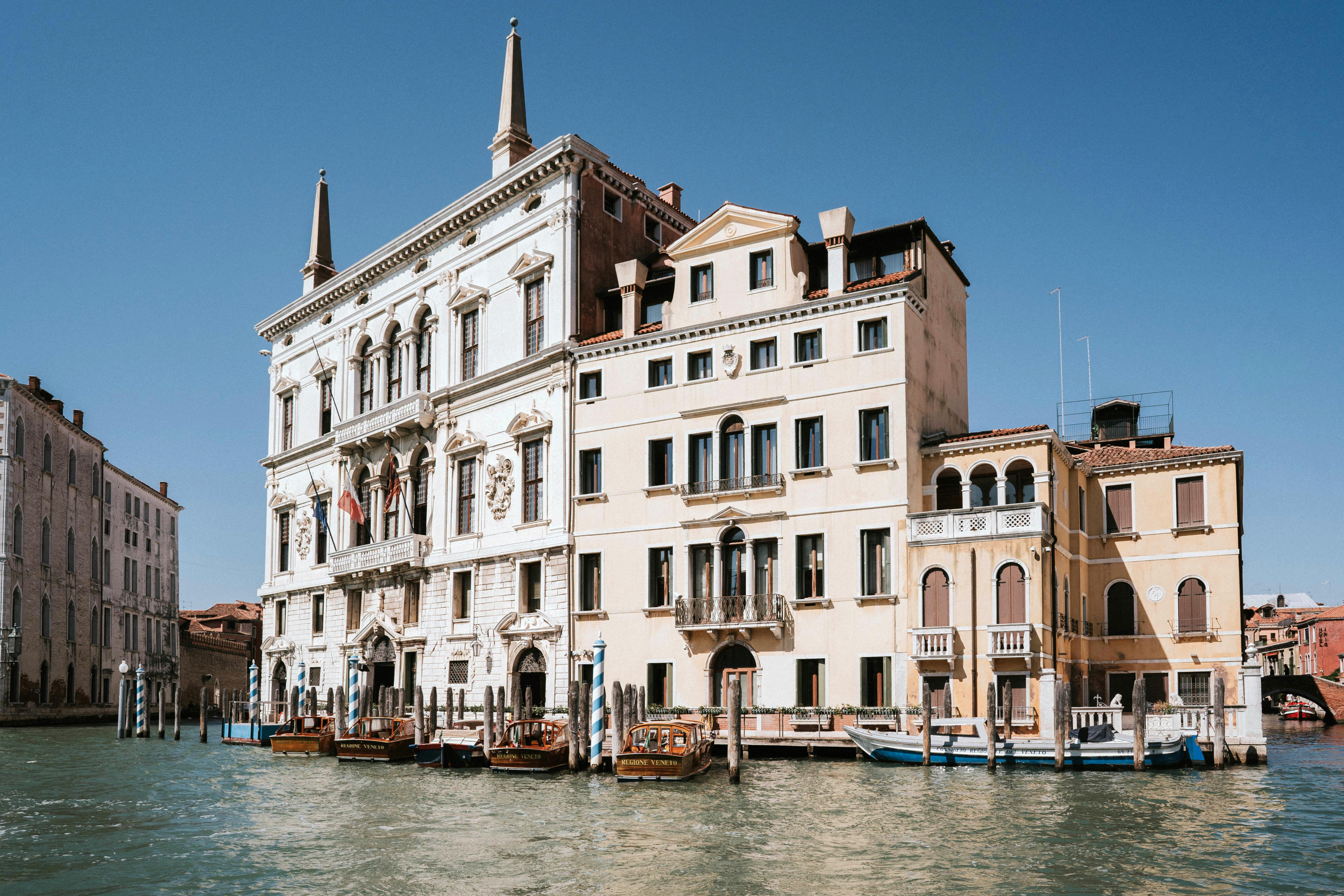 White Concrete Building near River under Blue Sky · Free Stock Photo