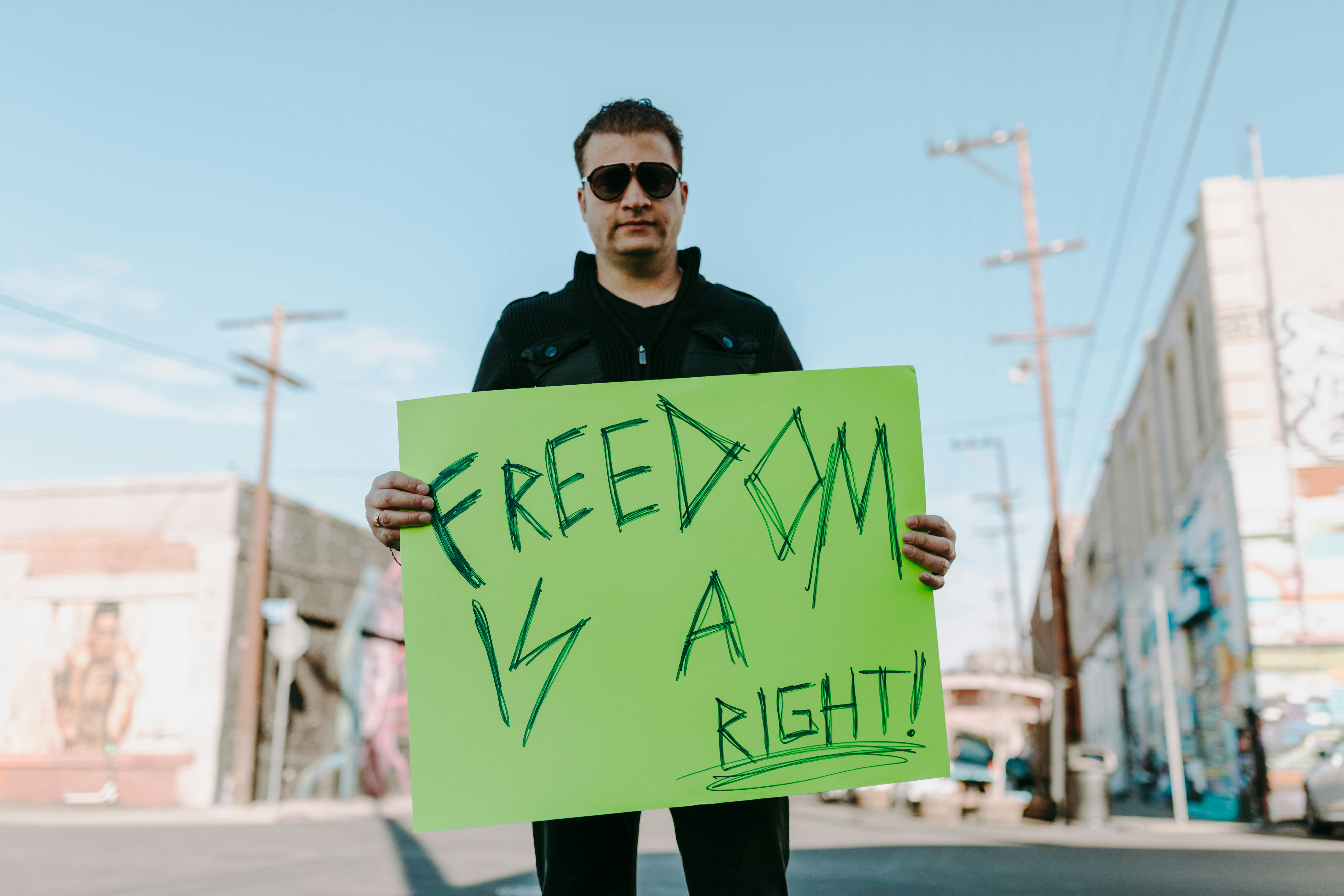 Man with Sunglasses Holding a Placard on Freedom · Free Stock Photo