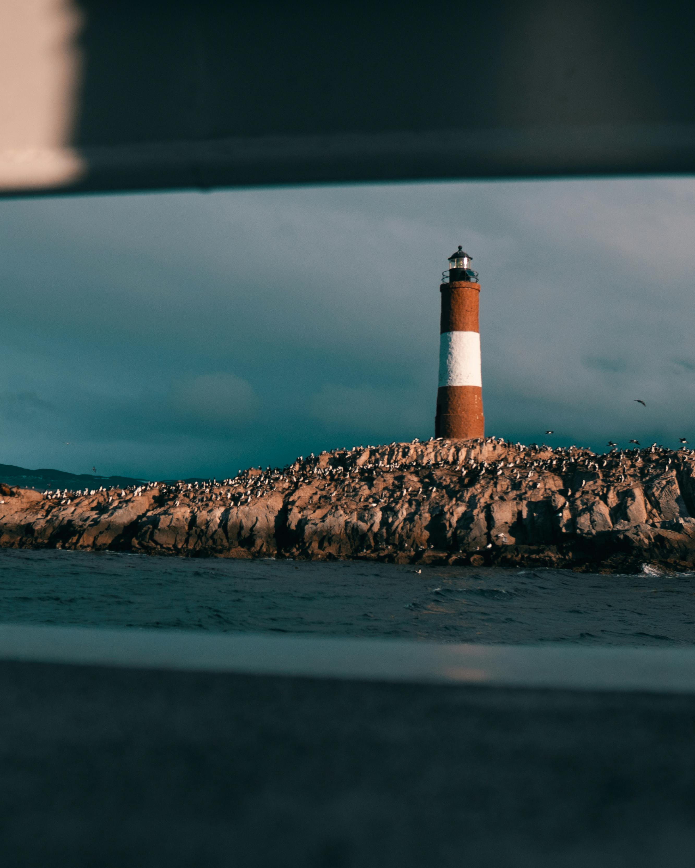 Faro Marrón Y Blanco En Brown Rocky Shore Bajo El Cielo Nublado Gris ...