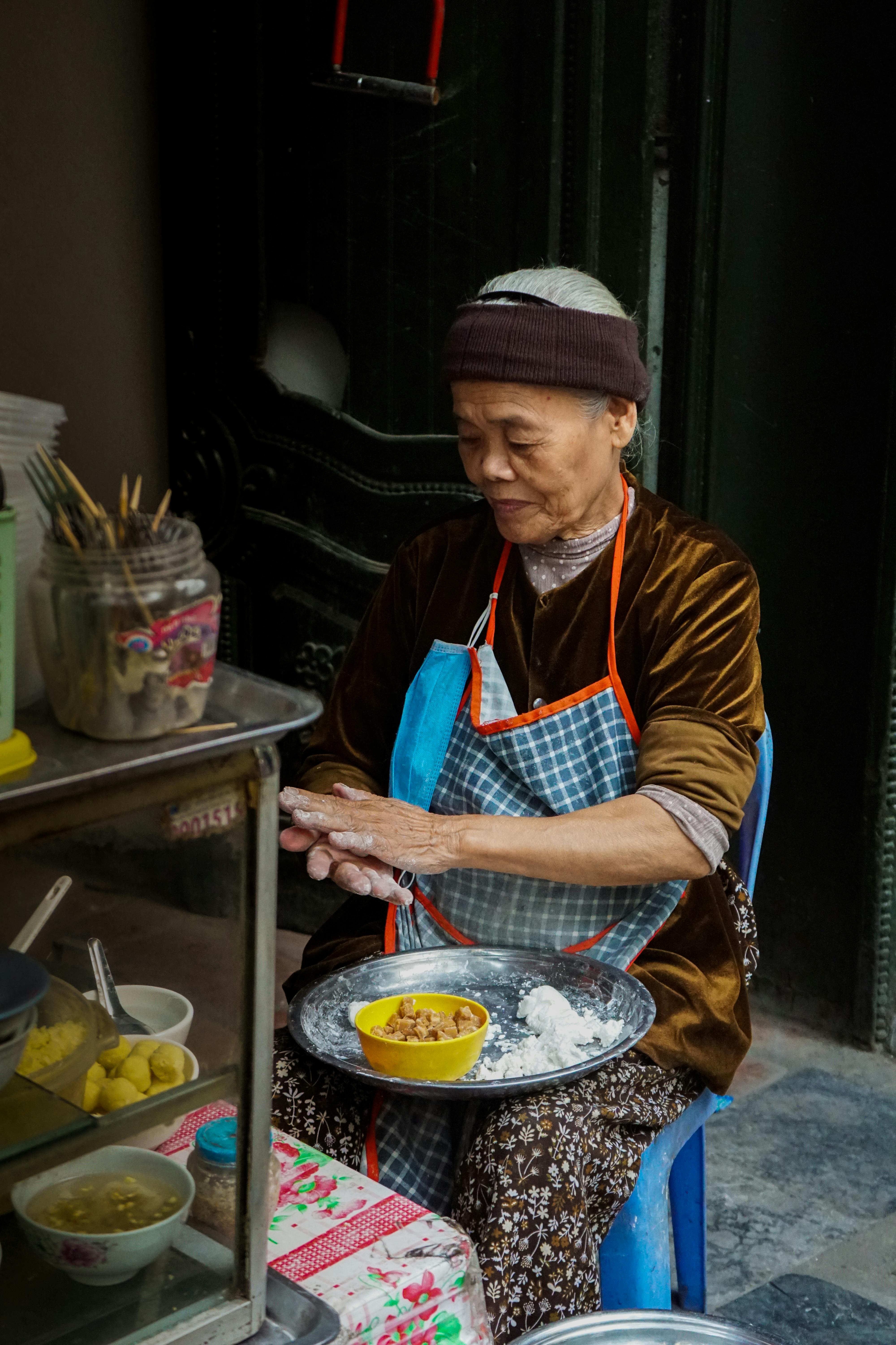 A Woman Preparing Food while Sitting · Free Stock Photo