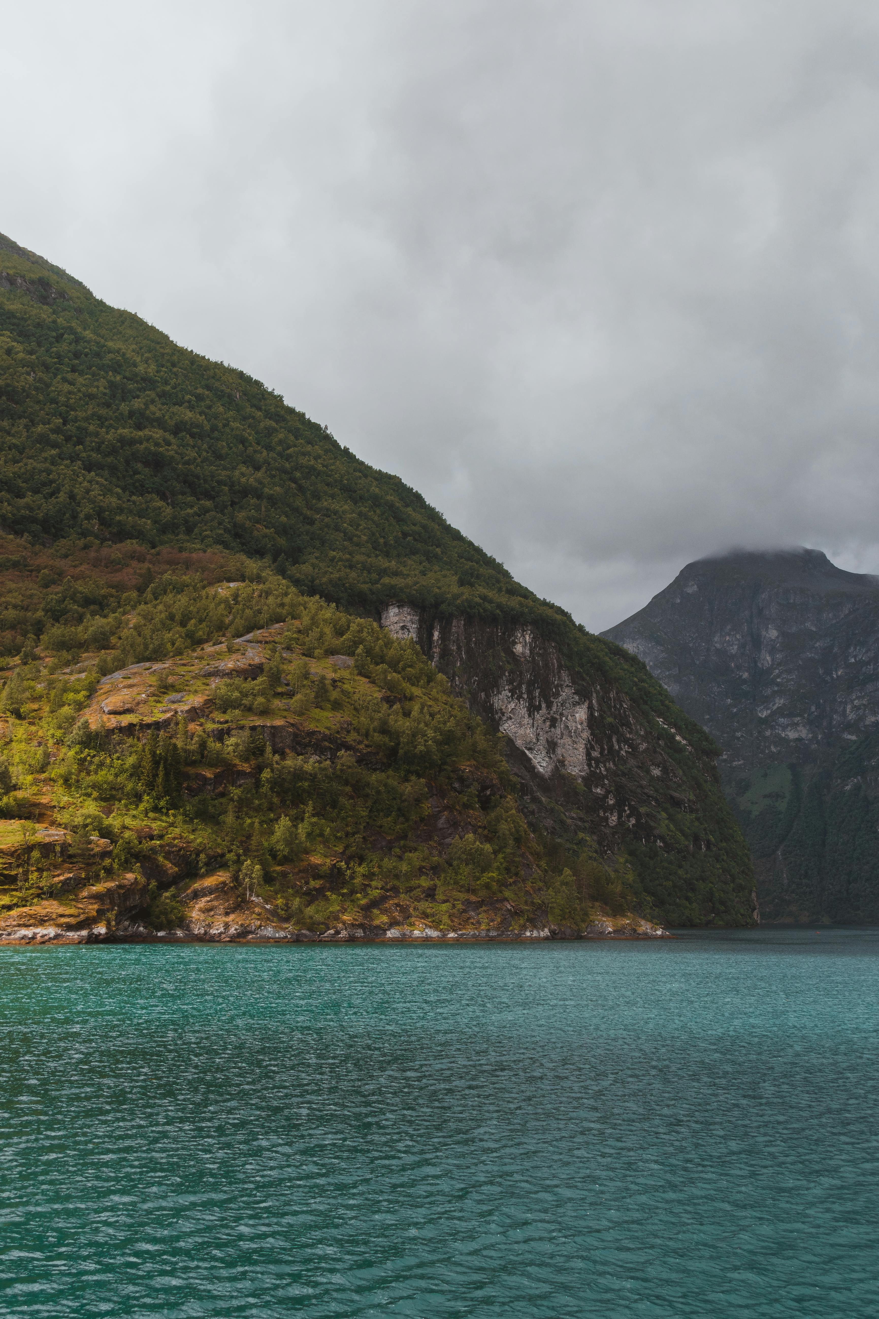 Sailboat floating in sea near rocky cliff · Free Stock Photo