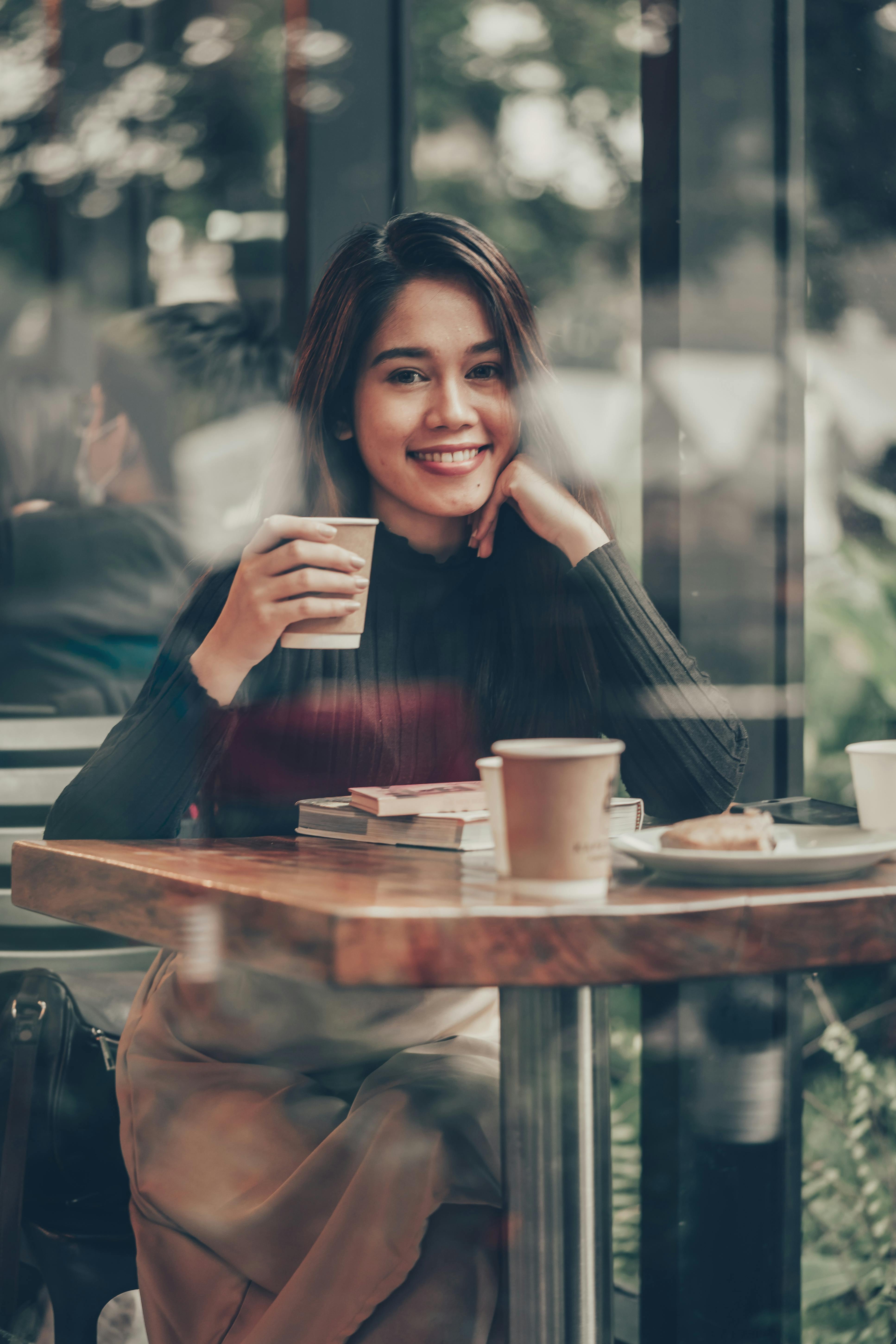 Photo of a Woman Smiling while Holding a Cup of Coffee · Free Stock Photo