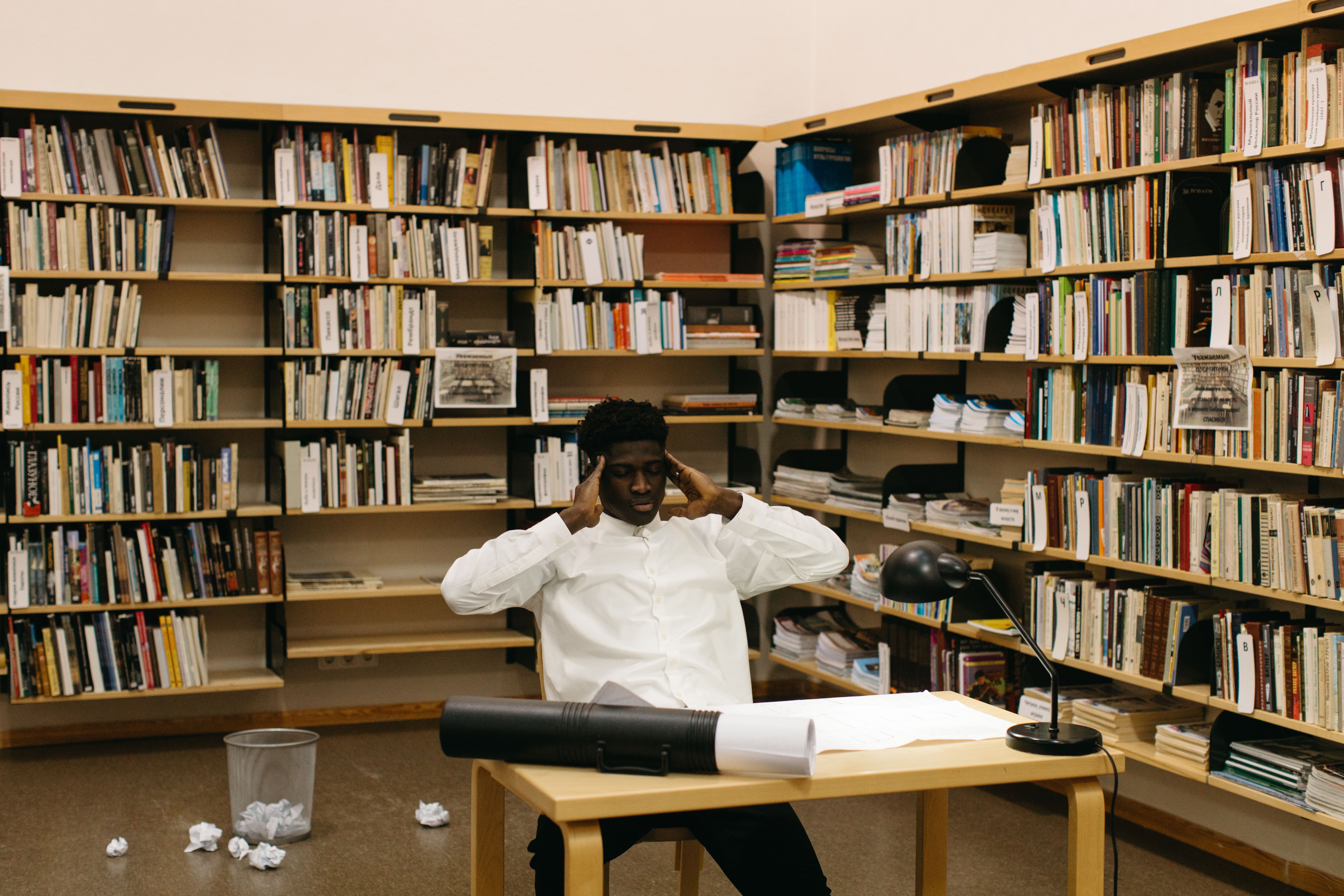 A Man Thinking while Sitting Inside the Library · Free Stock Photo