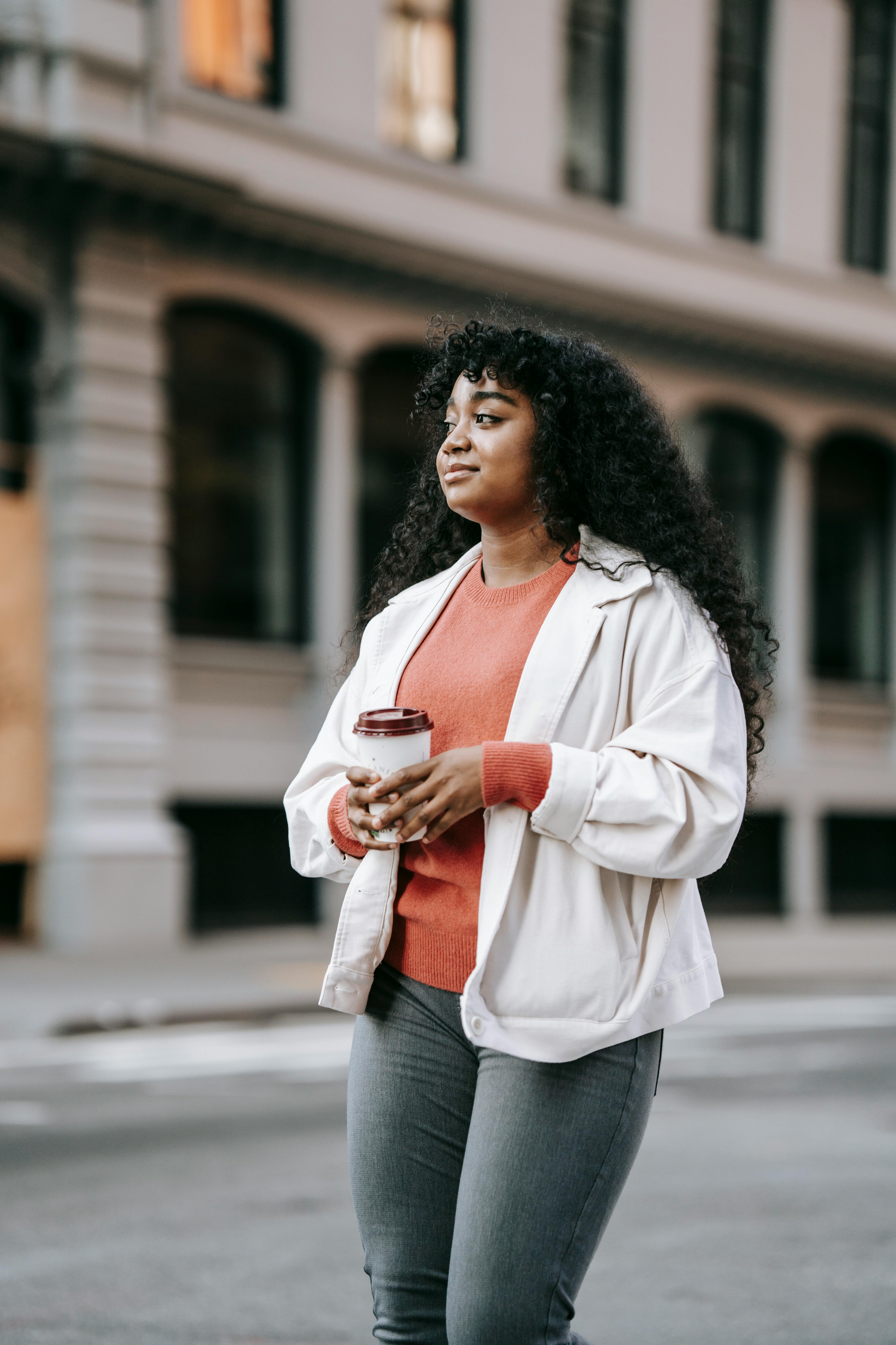 Black lady walking in town with takeaway drink in street · Free Stock Photo