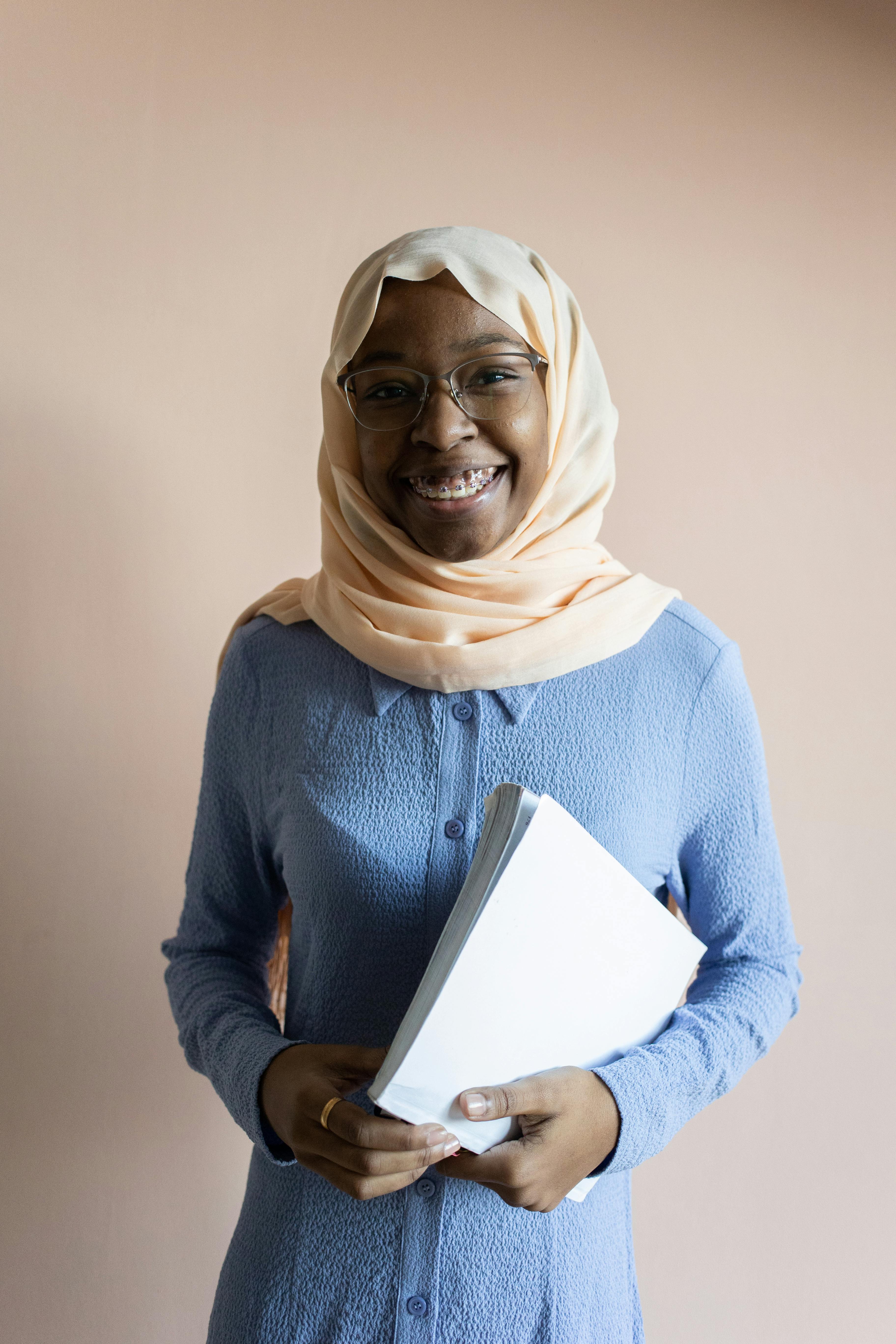 Smiling black female student in hijab with papers · Free Stock Photo