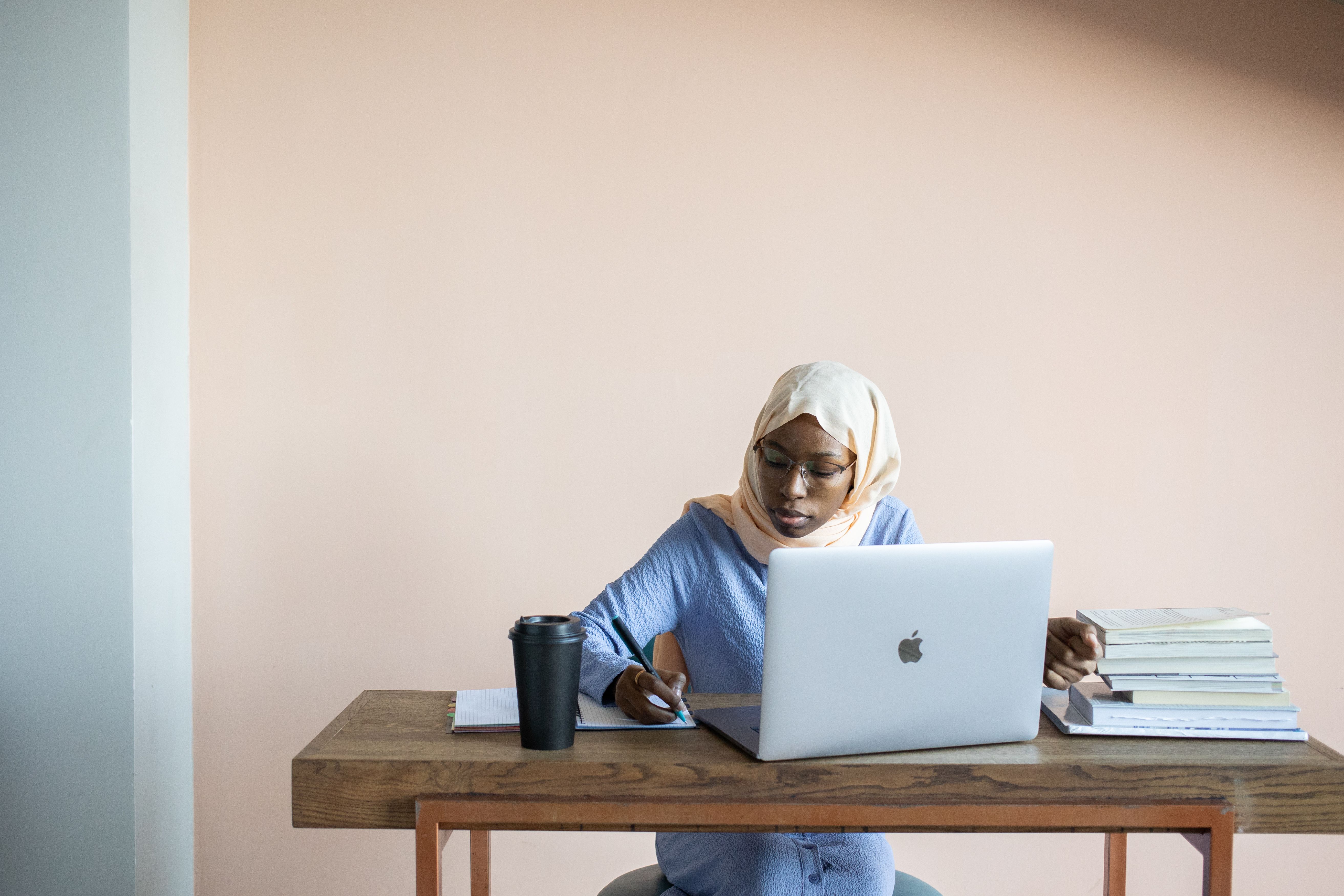 Positive woman using laptop and taking notes · Free Stock Photo